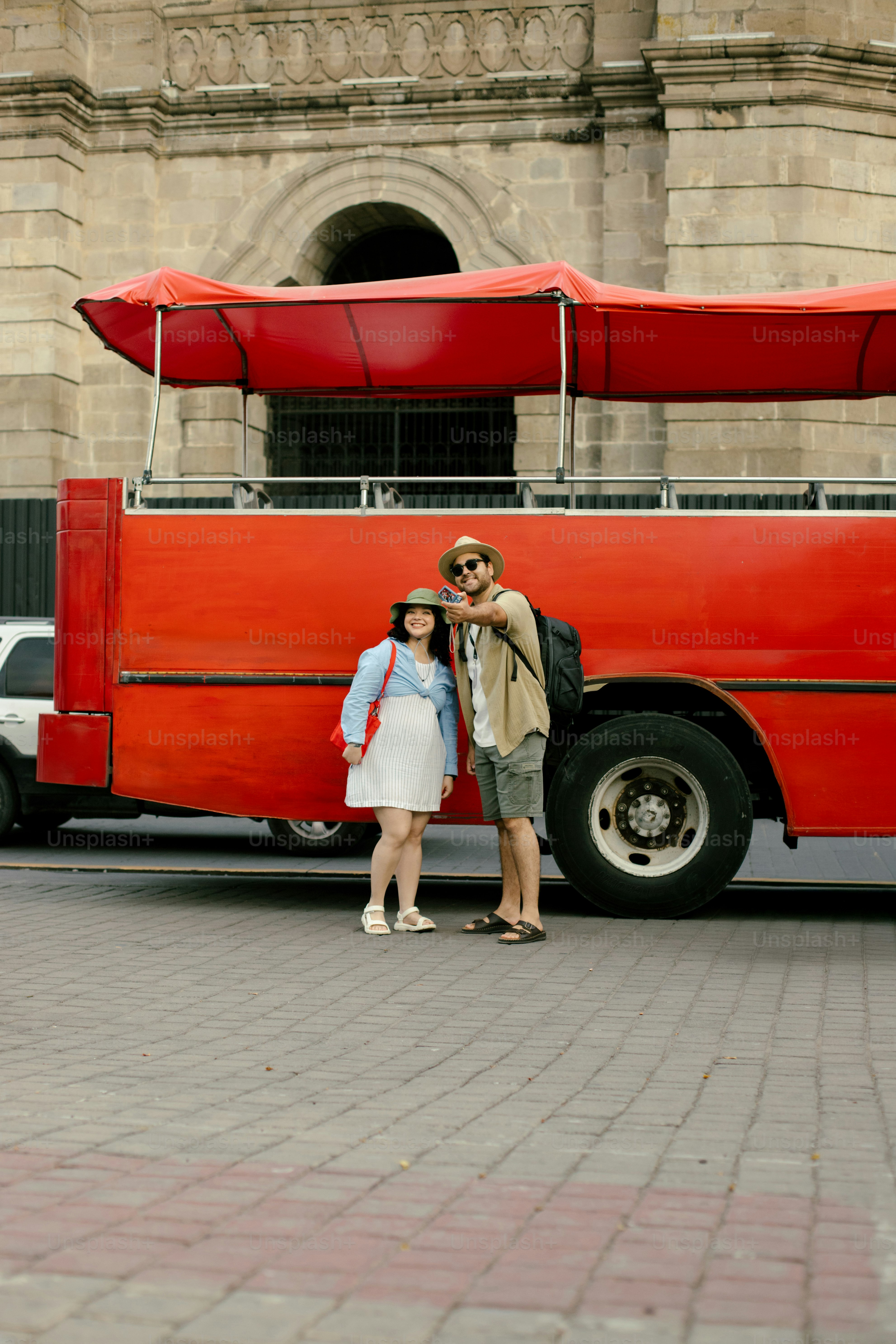 Couple poses in front of a red sightseeing bus. photo – Travel Image on ...