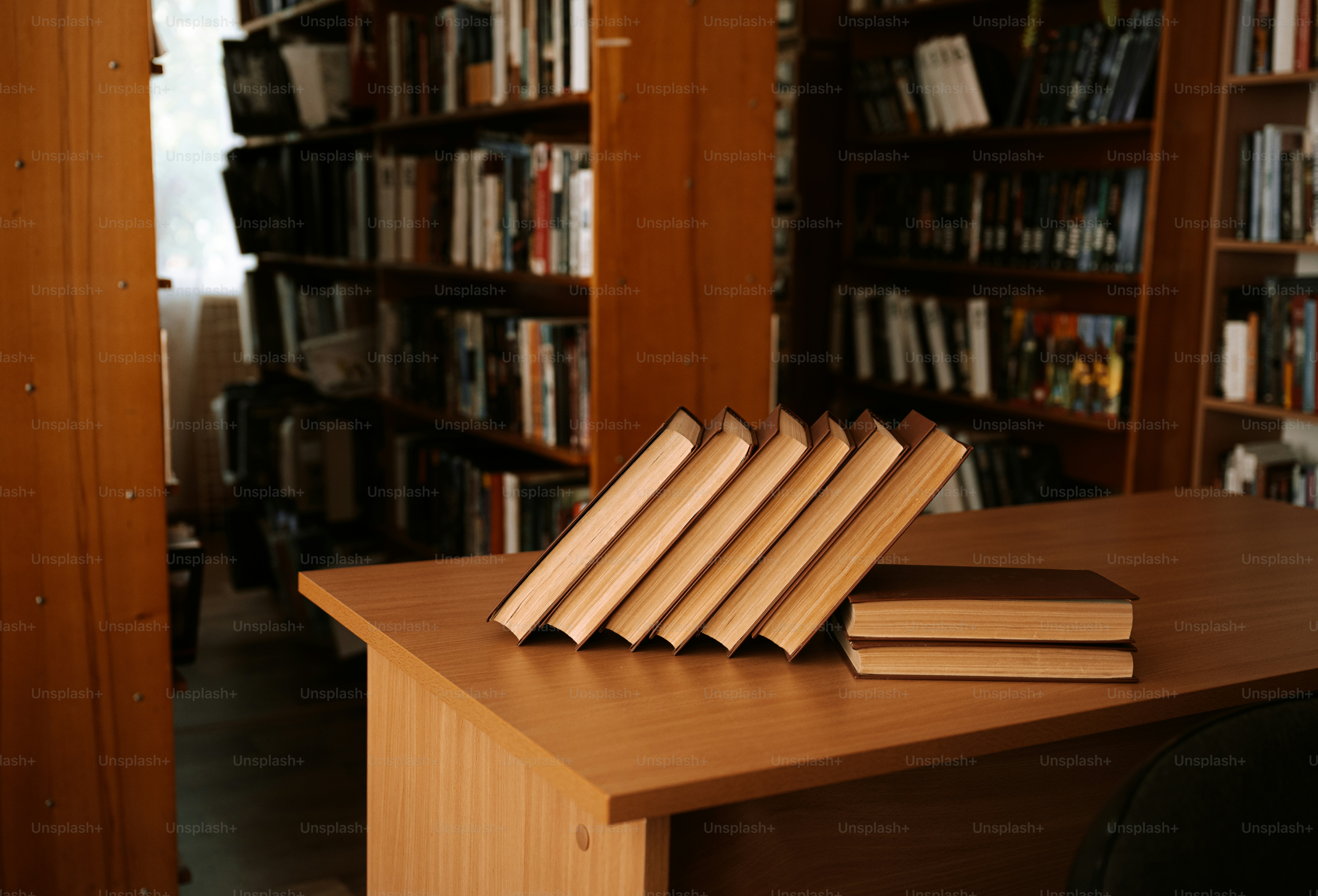 Books rest on a desk in a library. photo – Books Image on Unsplash