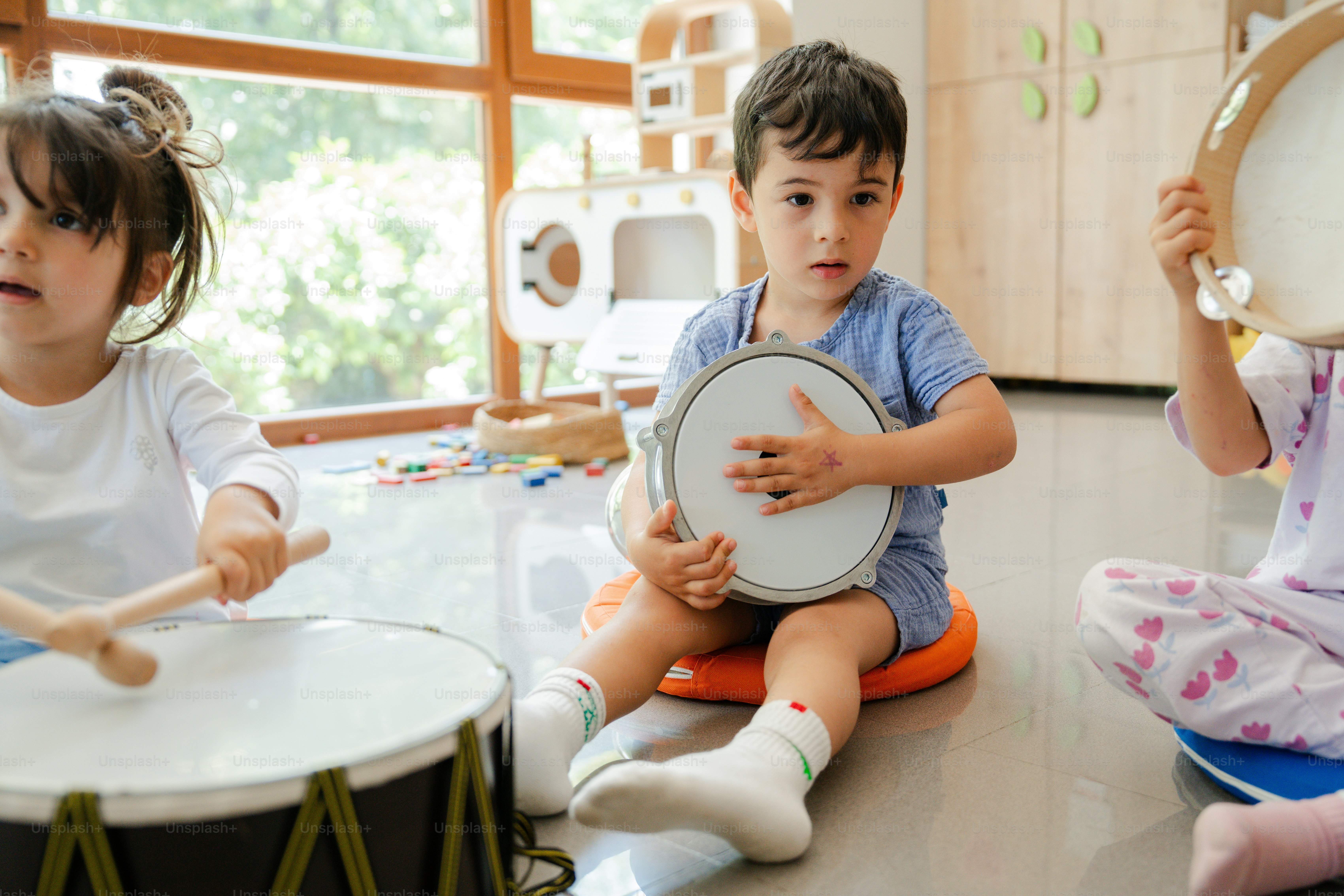 Children play tambourines in a classroom setting. photo – Kids Image on ...