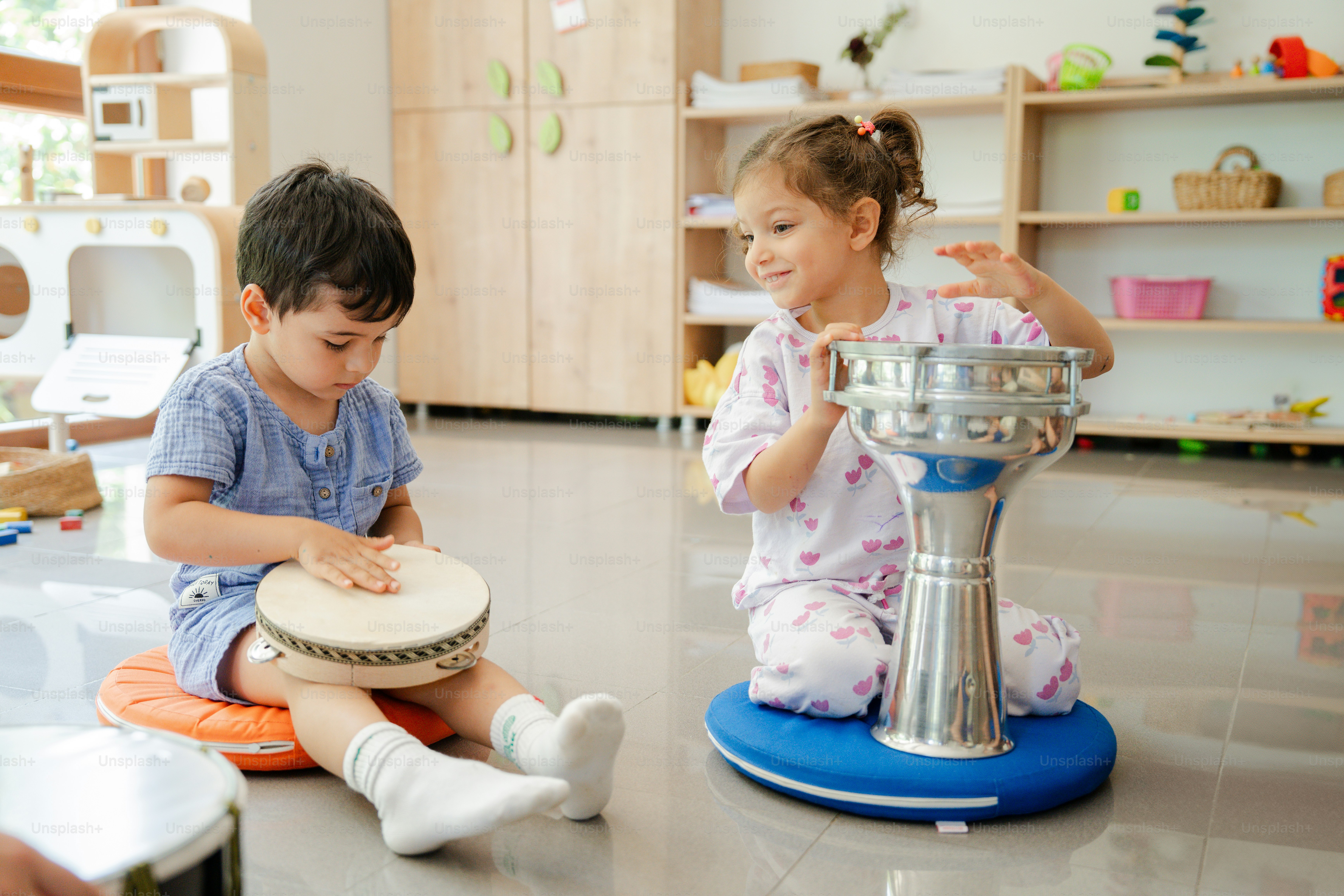 Two children play percussion instruments in a classroom. photo – Kids ...