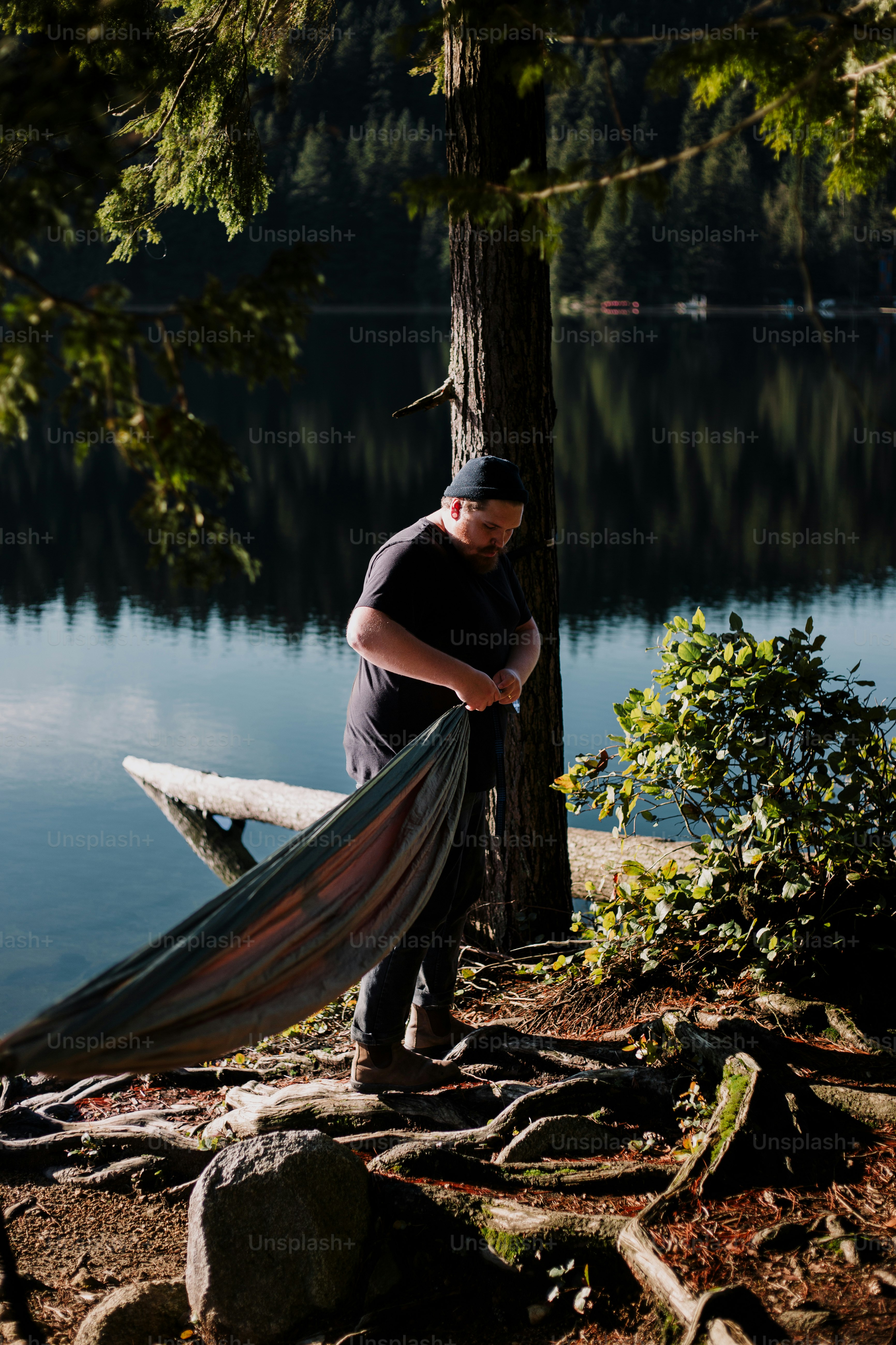 A man sets up a hammock by the lake. photo – Canada Image on Unsplash