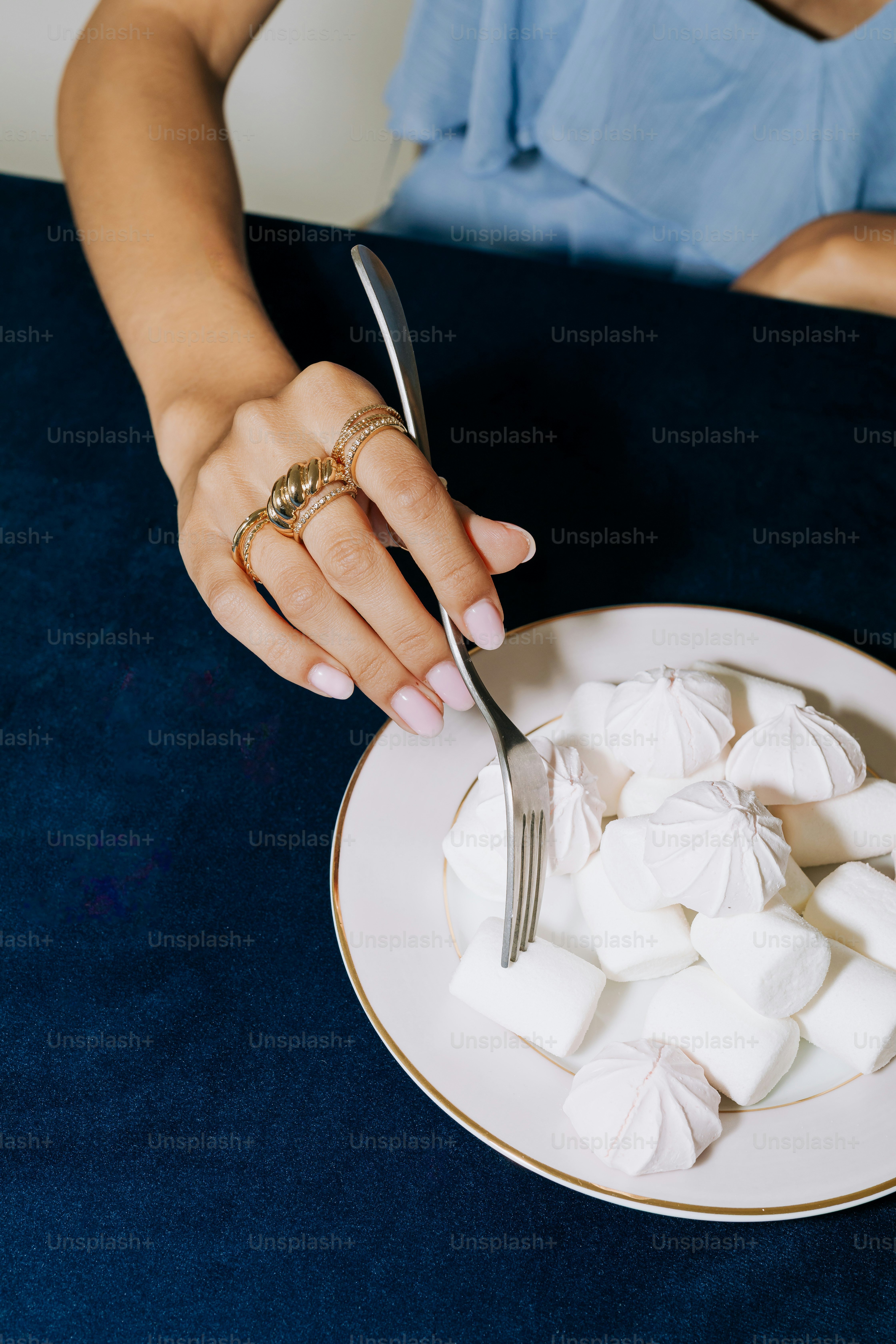 A hand holds a fork over a plate of marshmallows. photo – Flash Image ...