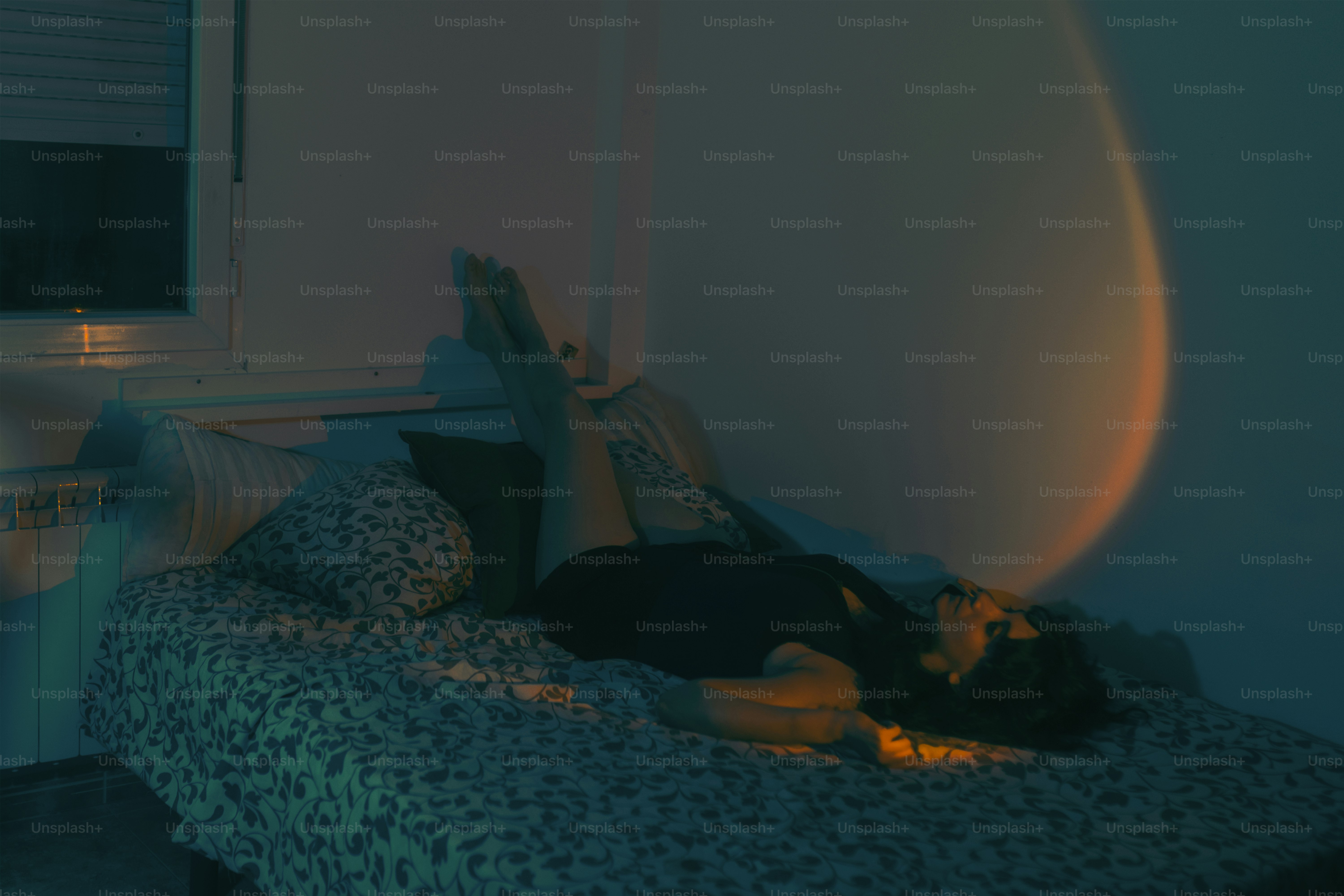 A person lies in bed with a warm, glowing light. photo – Woman Image on ...