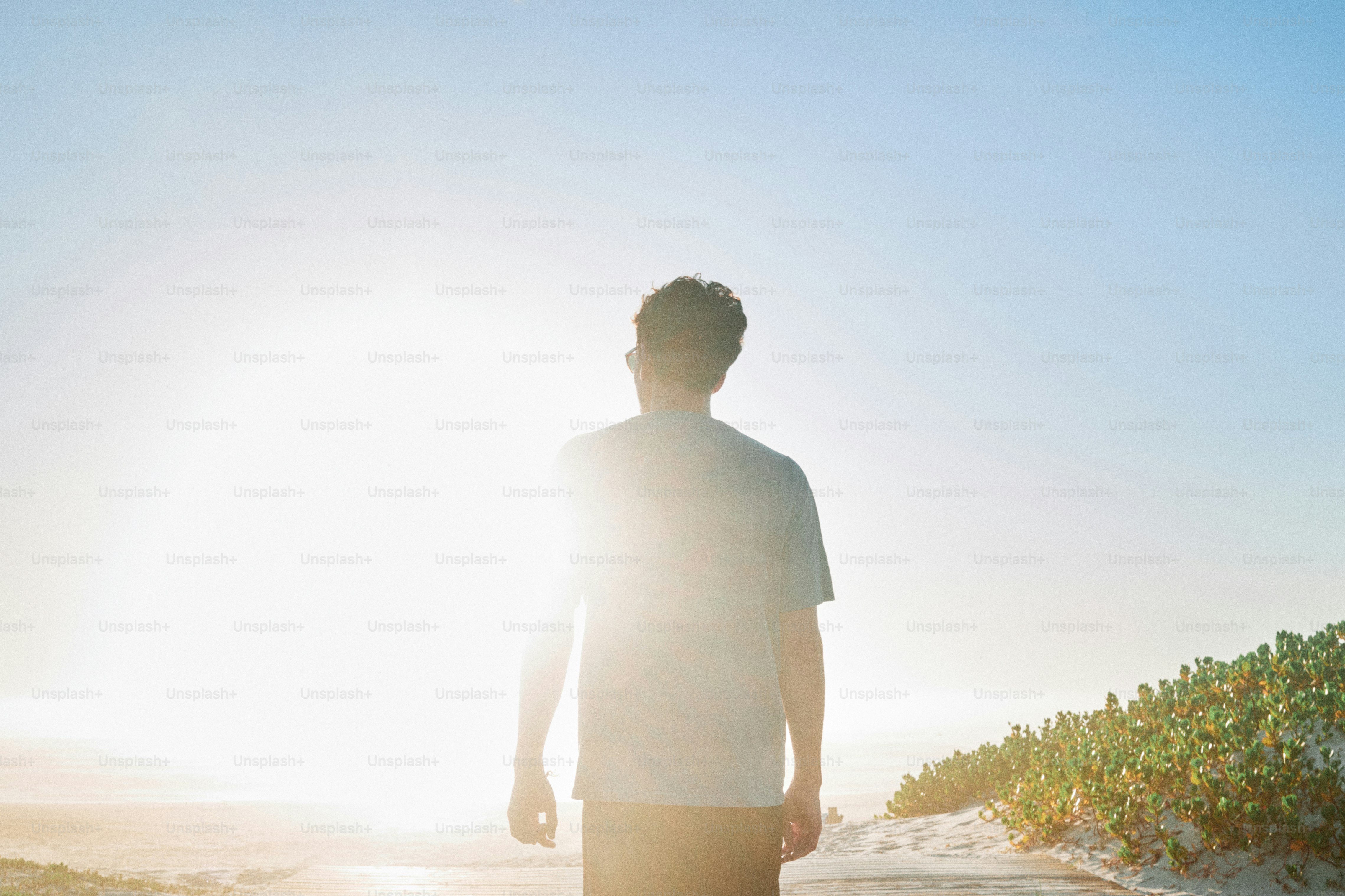Man with a towel looks out toward the ocean. photo – Portrait Image on ...