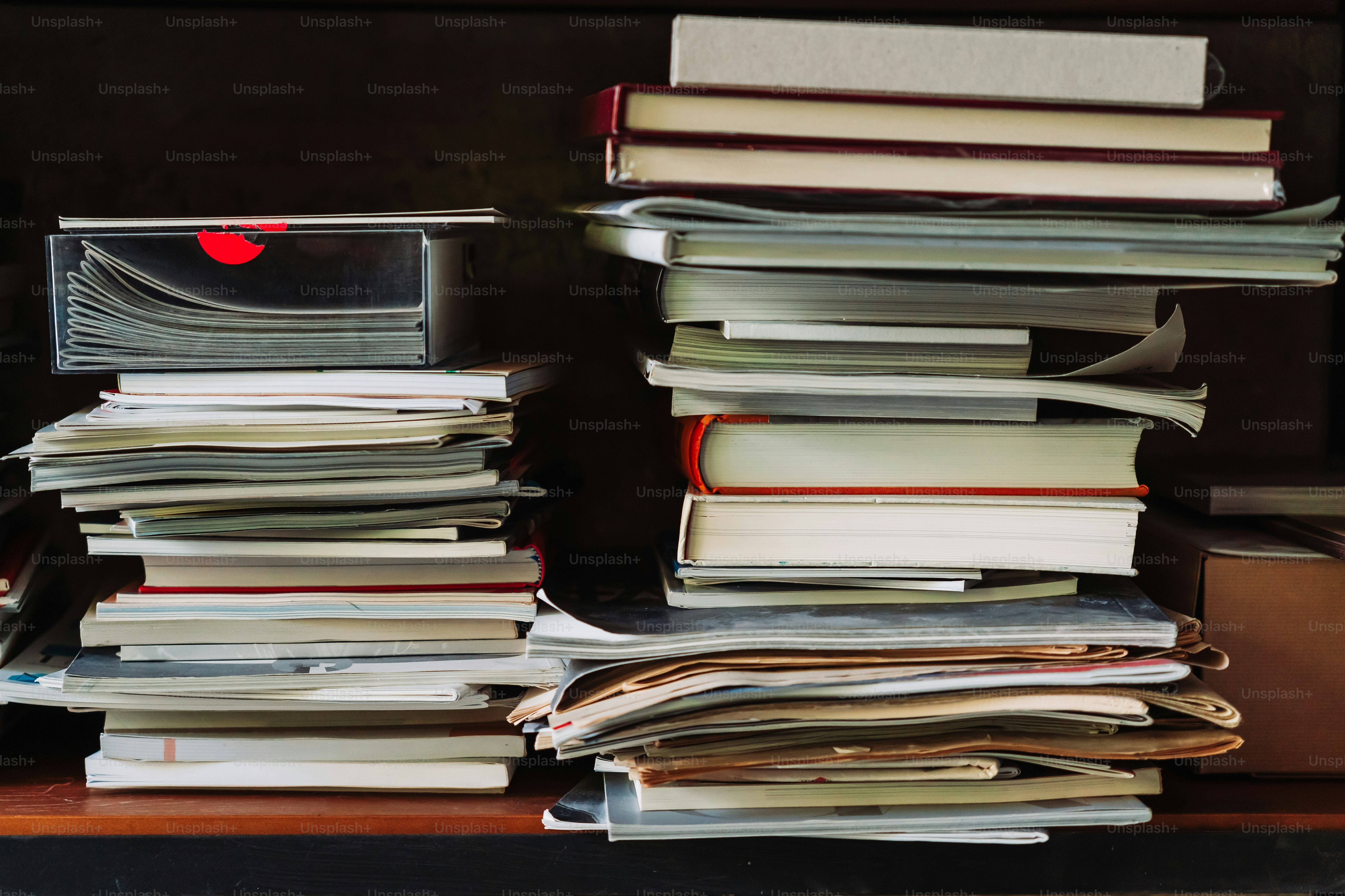 Stacks of papers and books sit on a shelf. photo – Books Image on Unsplash