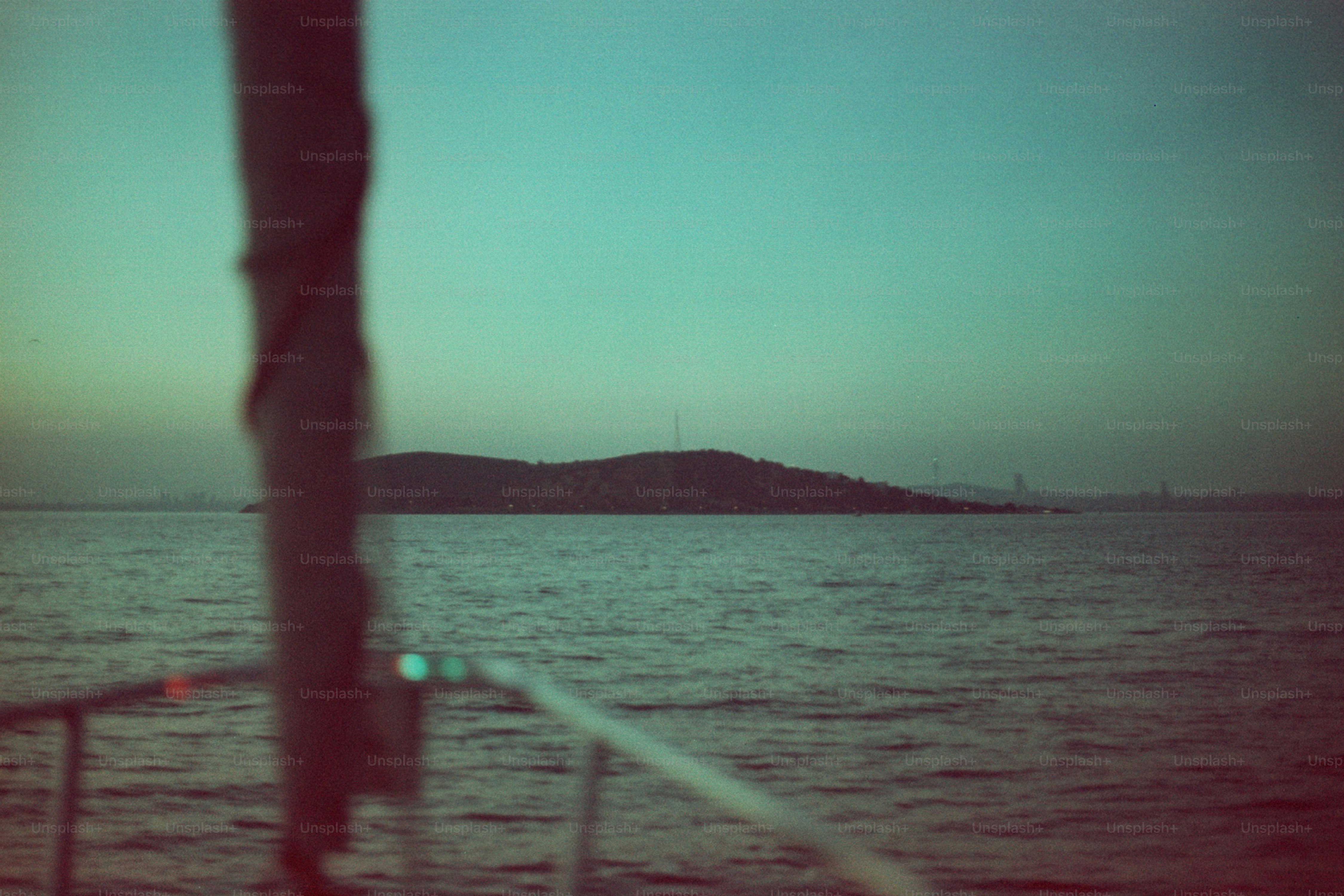Sailboat view of a distant island at dusk. photo – Film photography ...