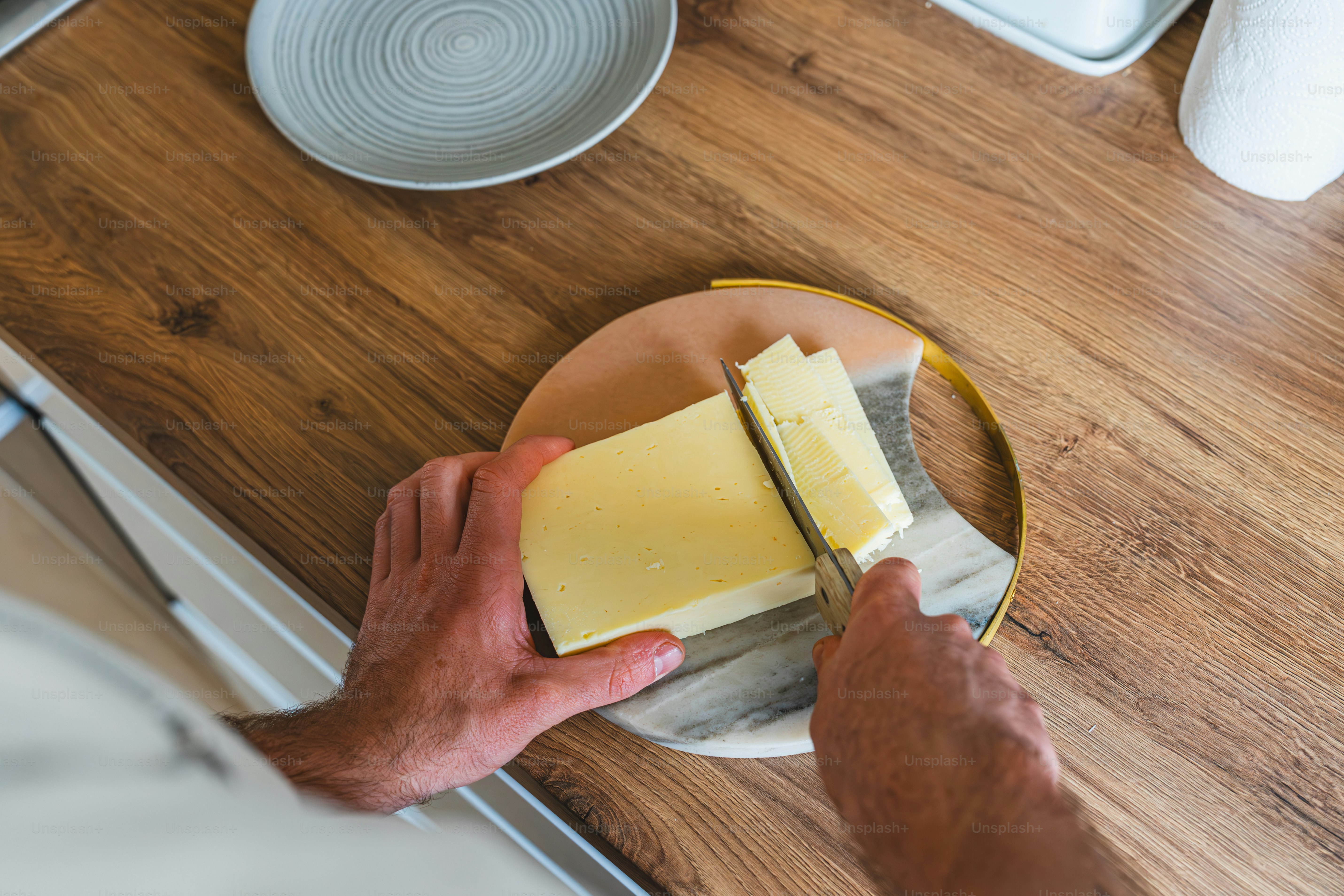 Una persona corta mantequilla sobre una superficie de madera. foto ...