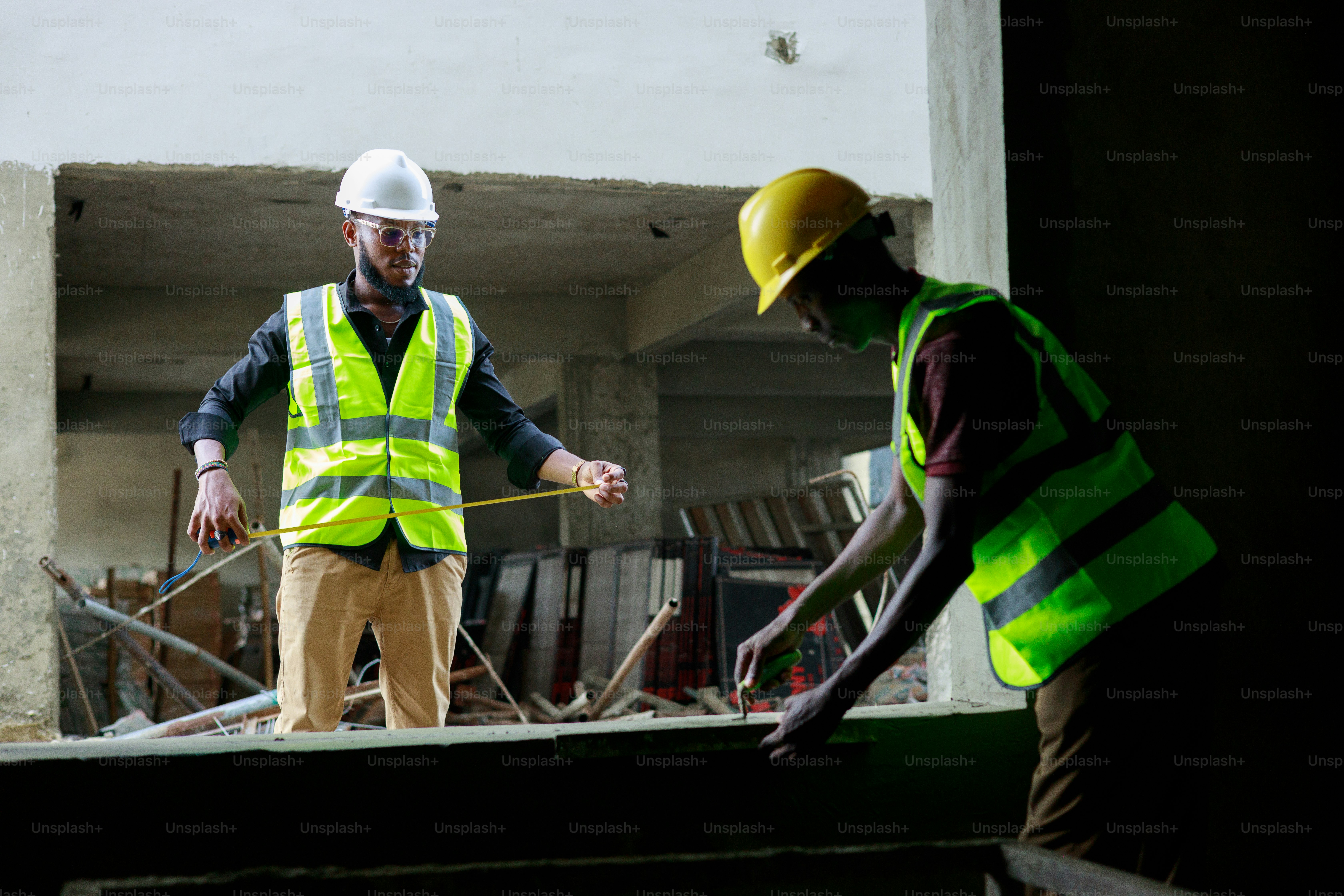 Construction workers measure something at a worksite. photo ...