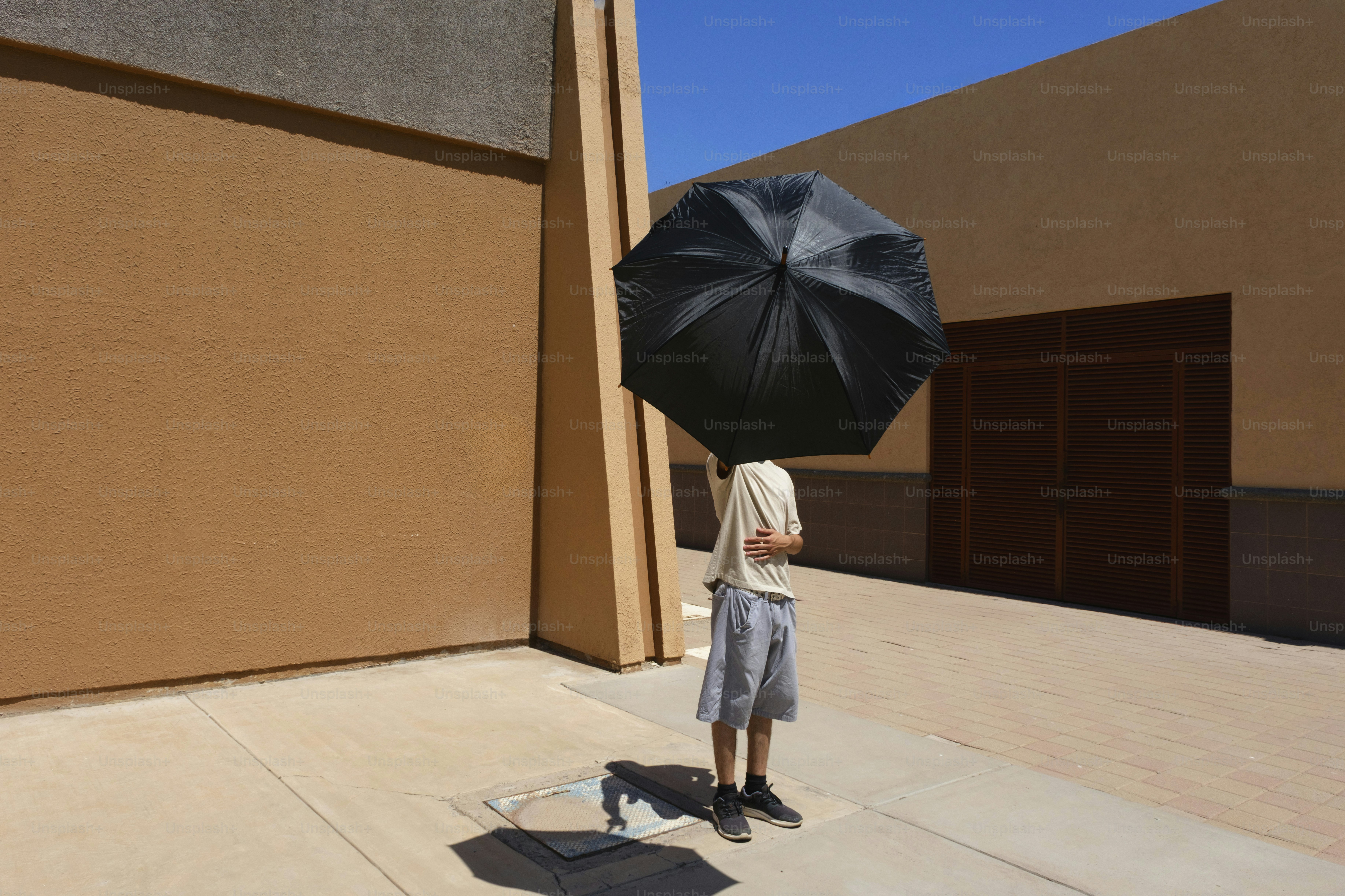 A person stands under an umbrella in the sun. photo – Portrait Image on Unsplash