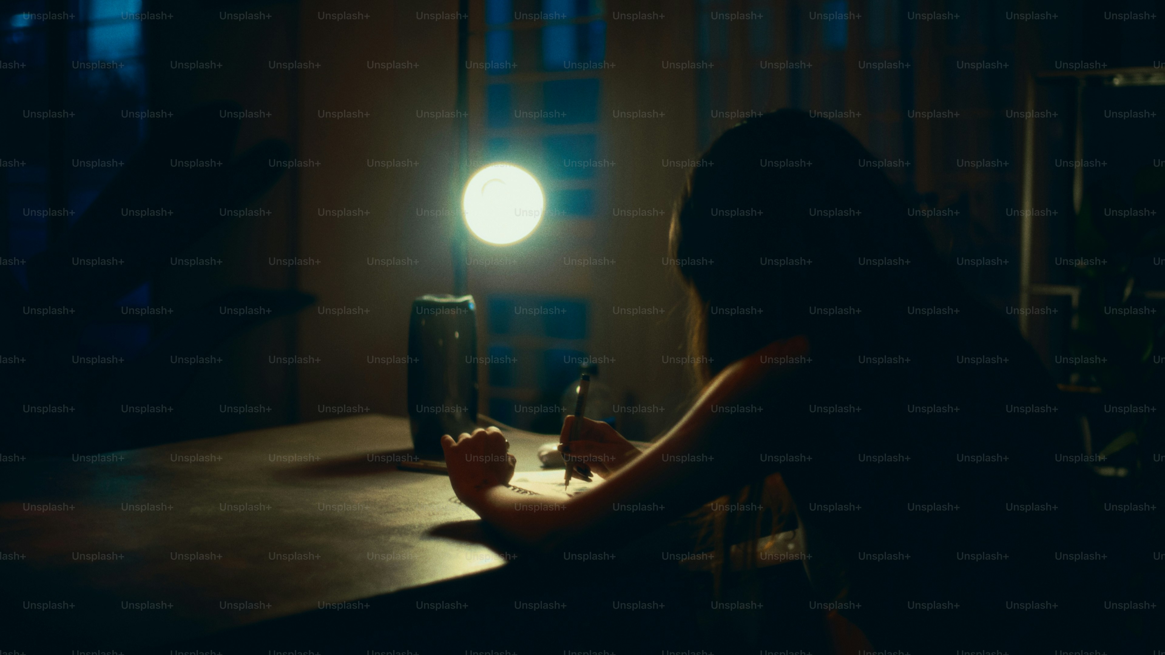 A woman writes under the dim glow of a lamp. photo – Cinematic Image on ...