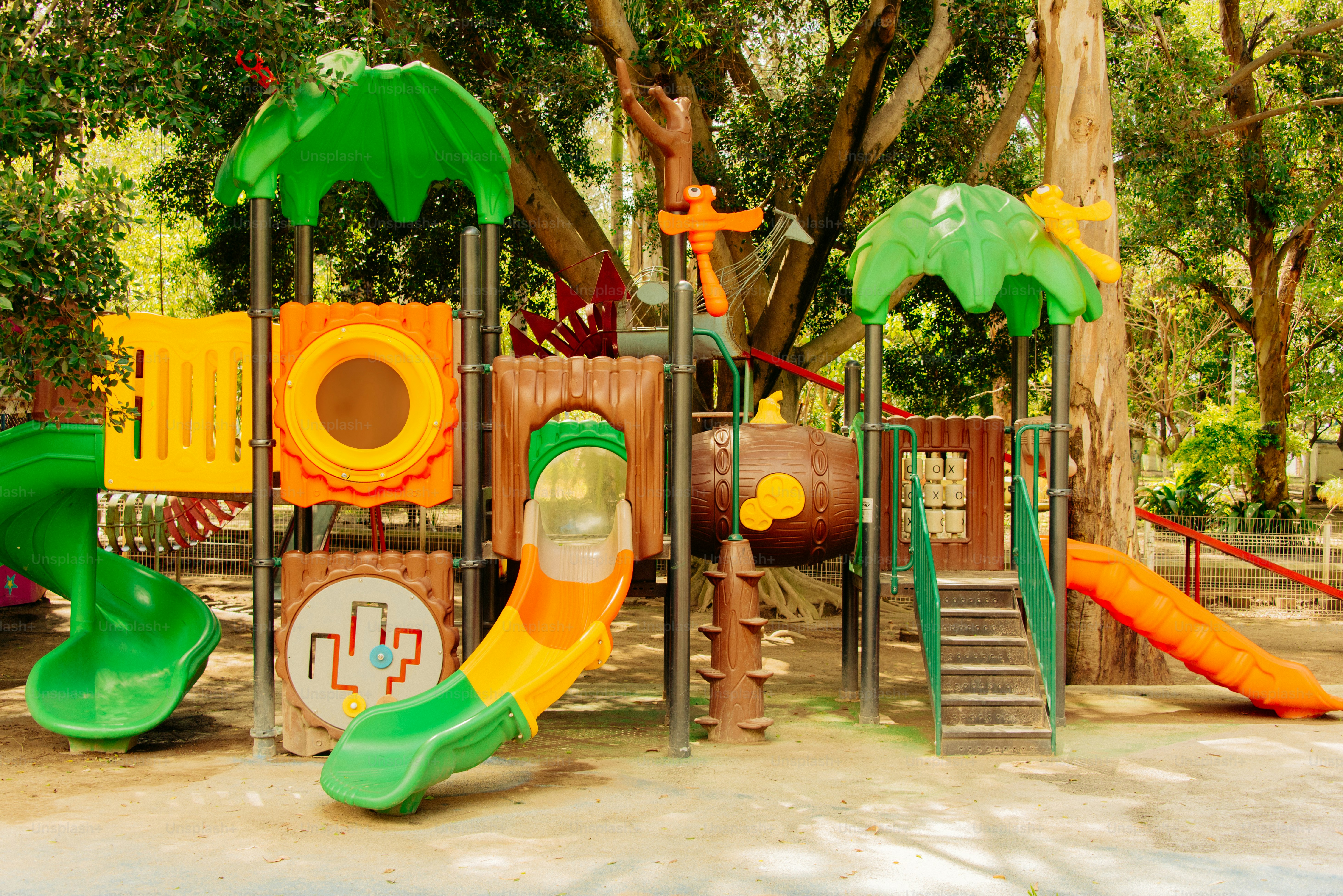 A colorful playground is surrounded by trees. photo – Park Image on ...