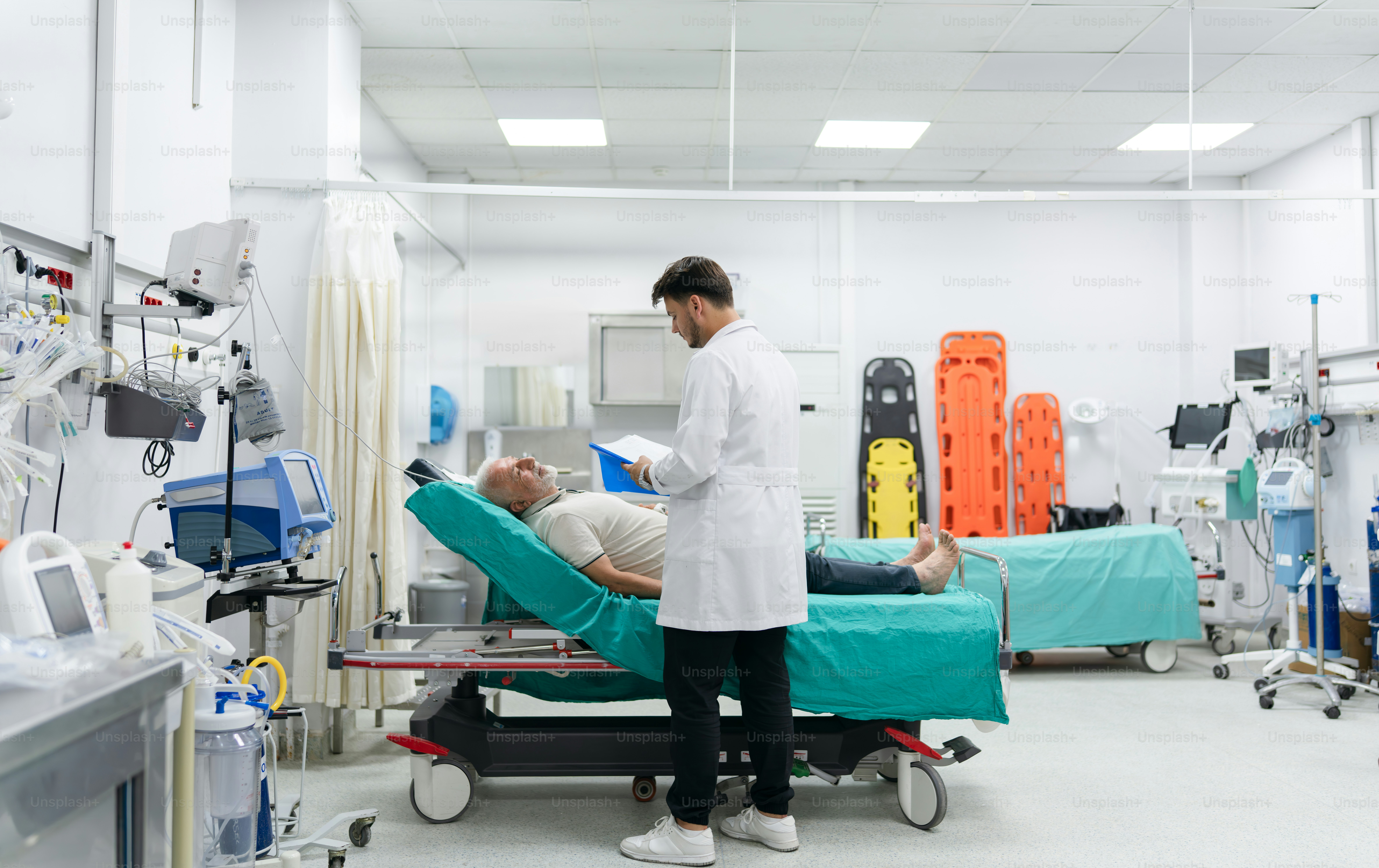 A doctor attends to a patient in a hospital room. photo – Hospital ...