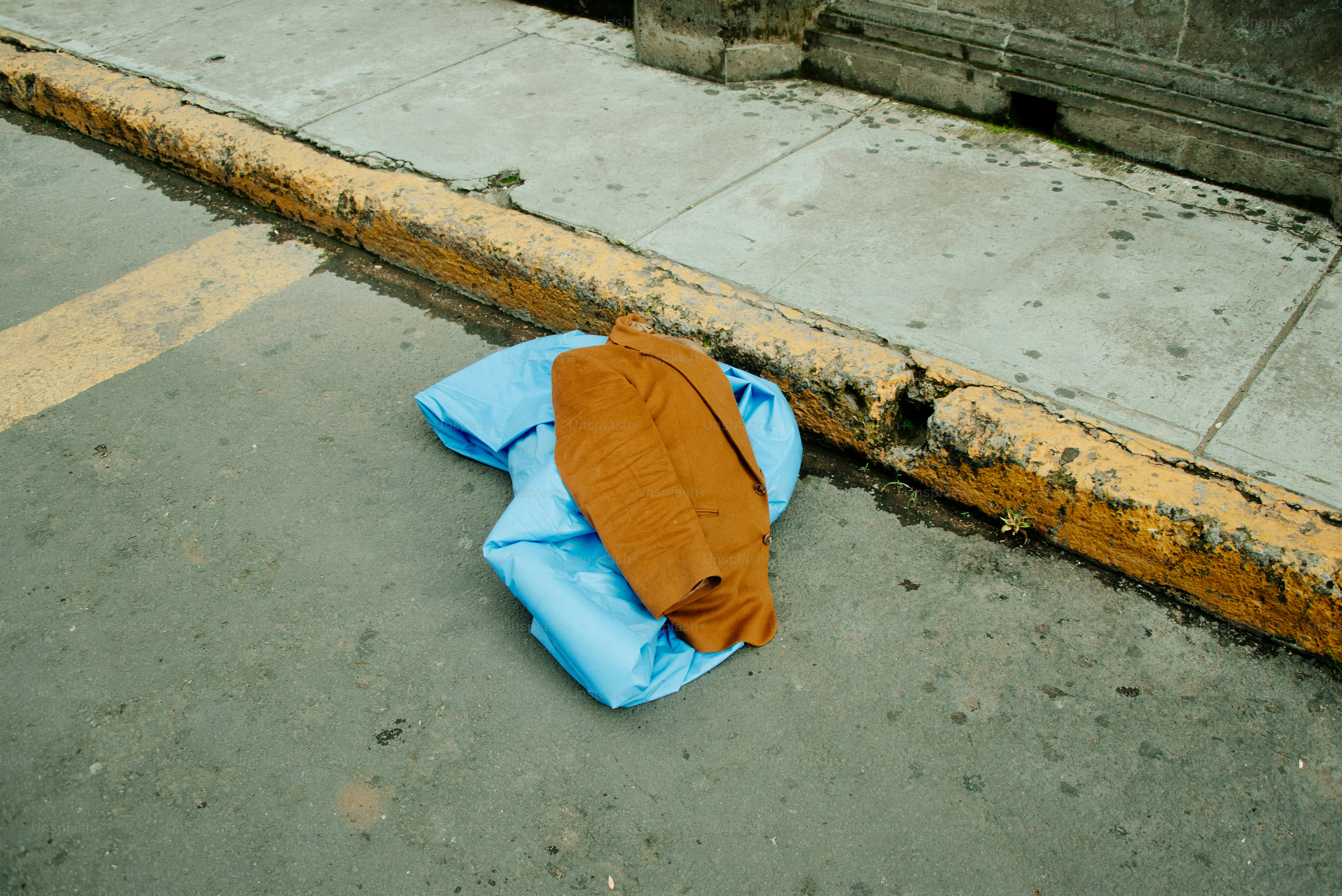 Clothes lay discarded on a sidewalk. photo – Street Image on Unsplash