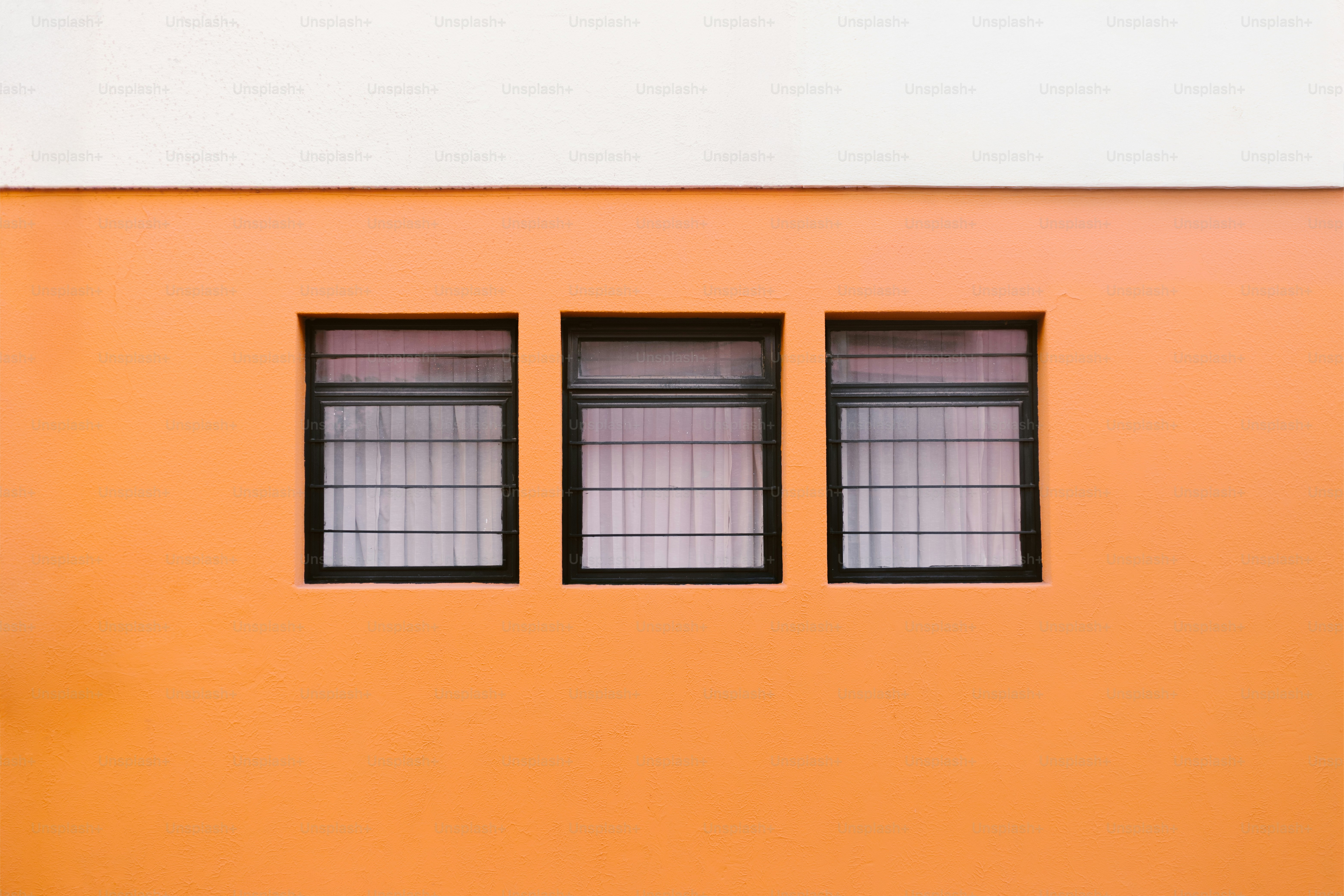 Three windows are in an orange and white wall. photo – Architecture ...