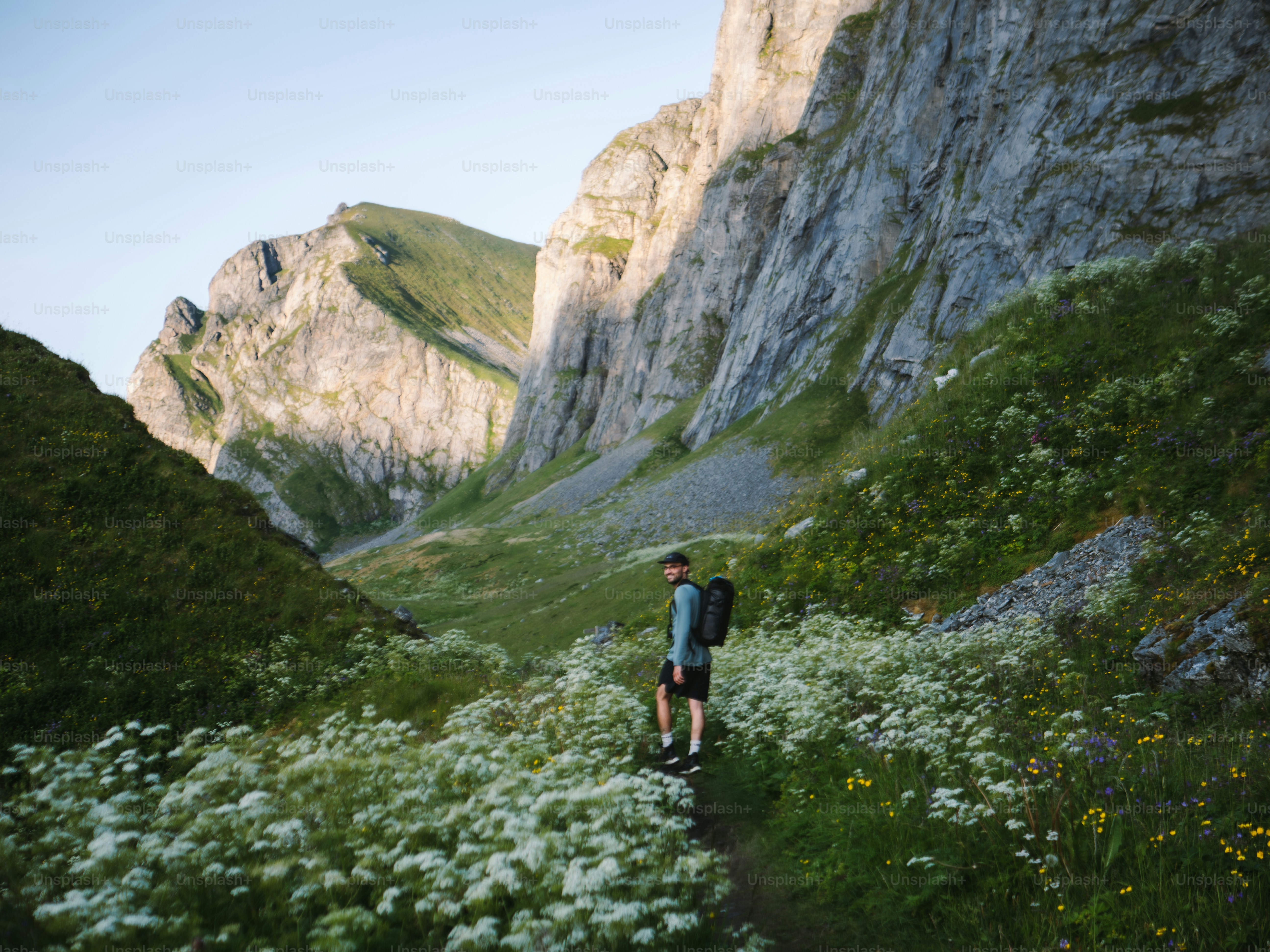 A hiker walks through a lush, mountainous valley. photo – Travel Image ...