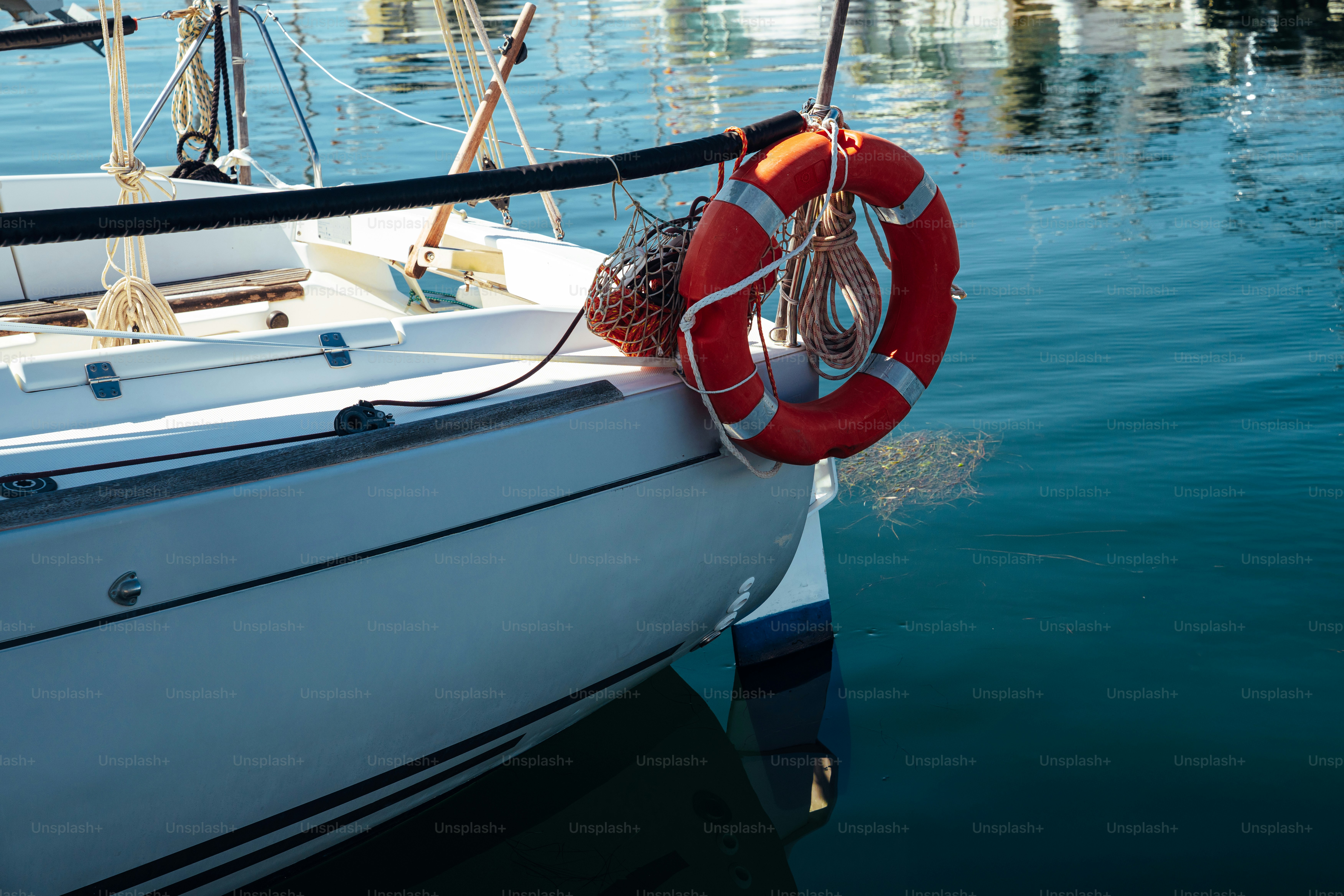 A boat with a life preserver floats on water. photo – Boating Image on ...
