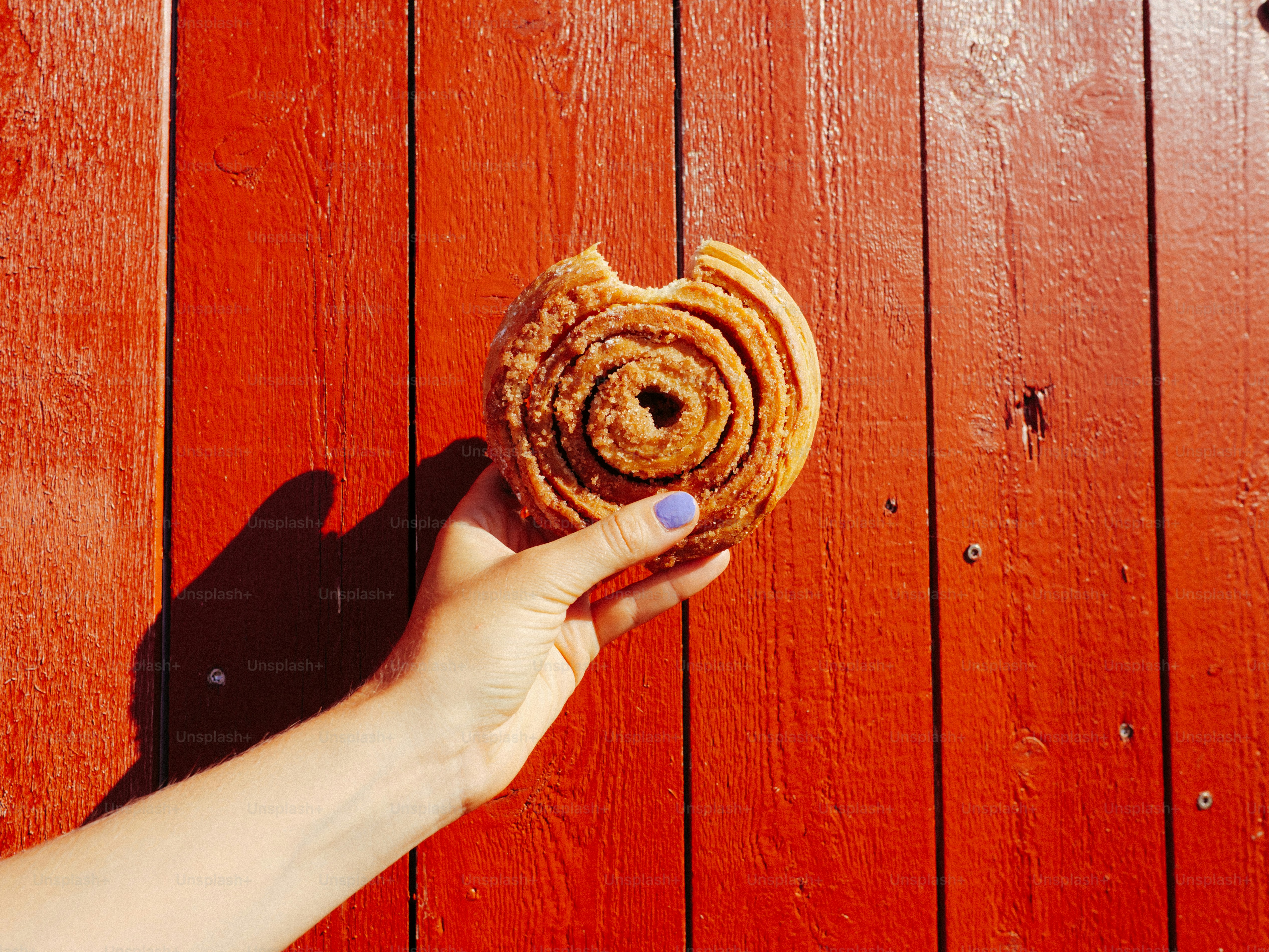 La main tenant un délicieux petit pain à la cannelle croqué. photo ...