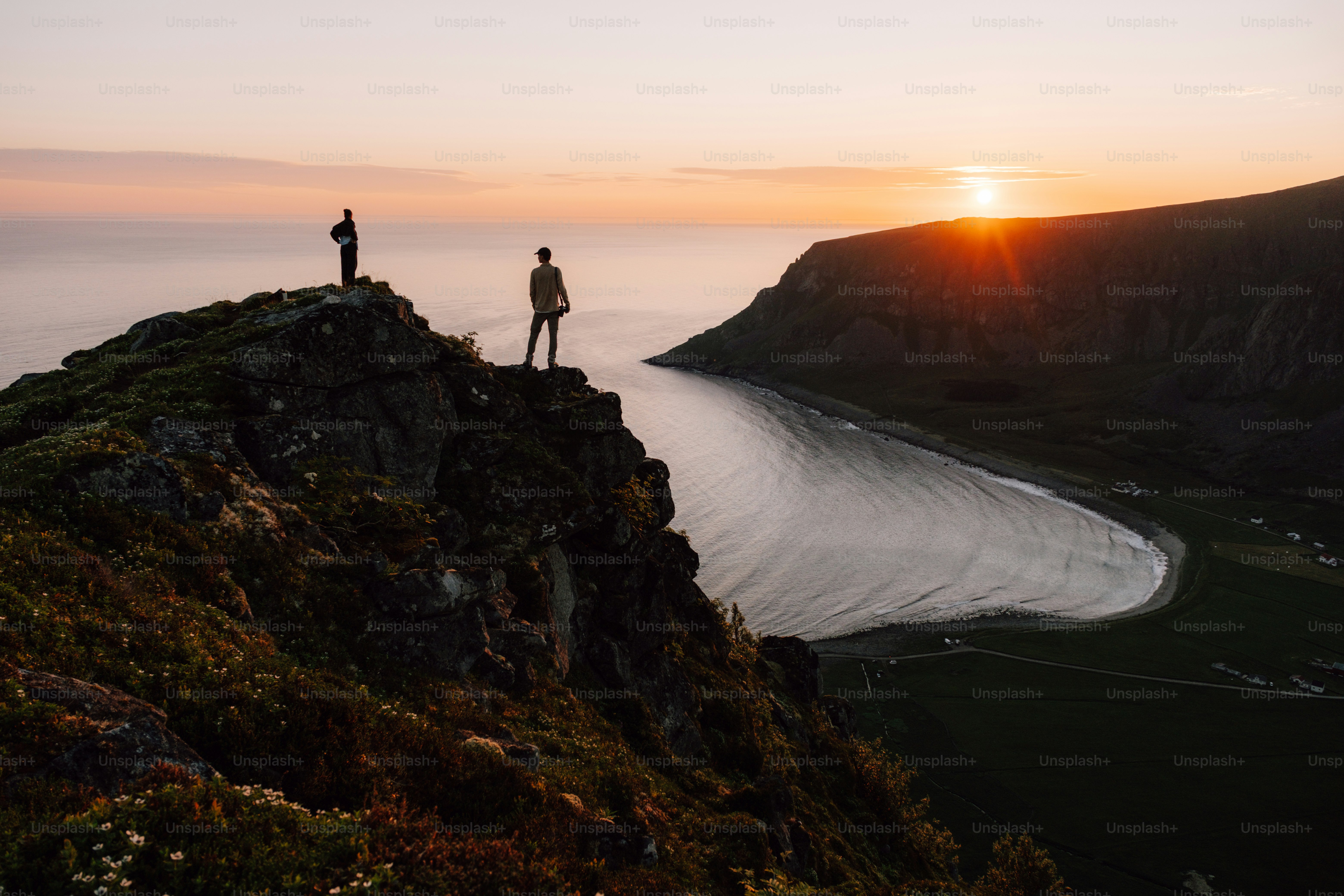 People on a cliff watch the sunset. photo – Travel Image on Unsplash