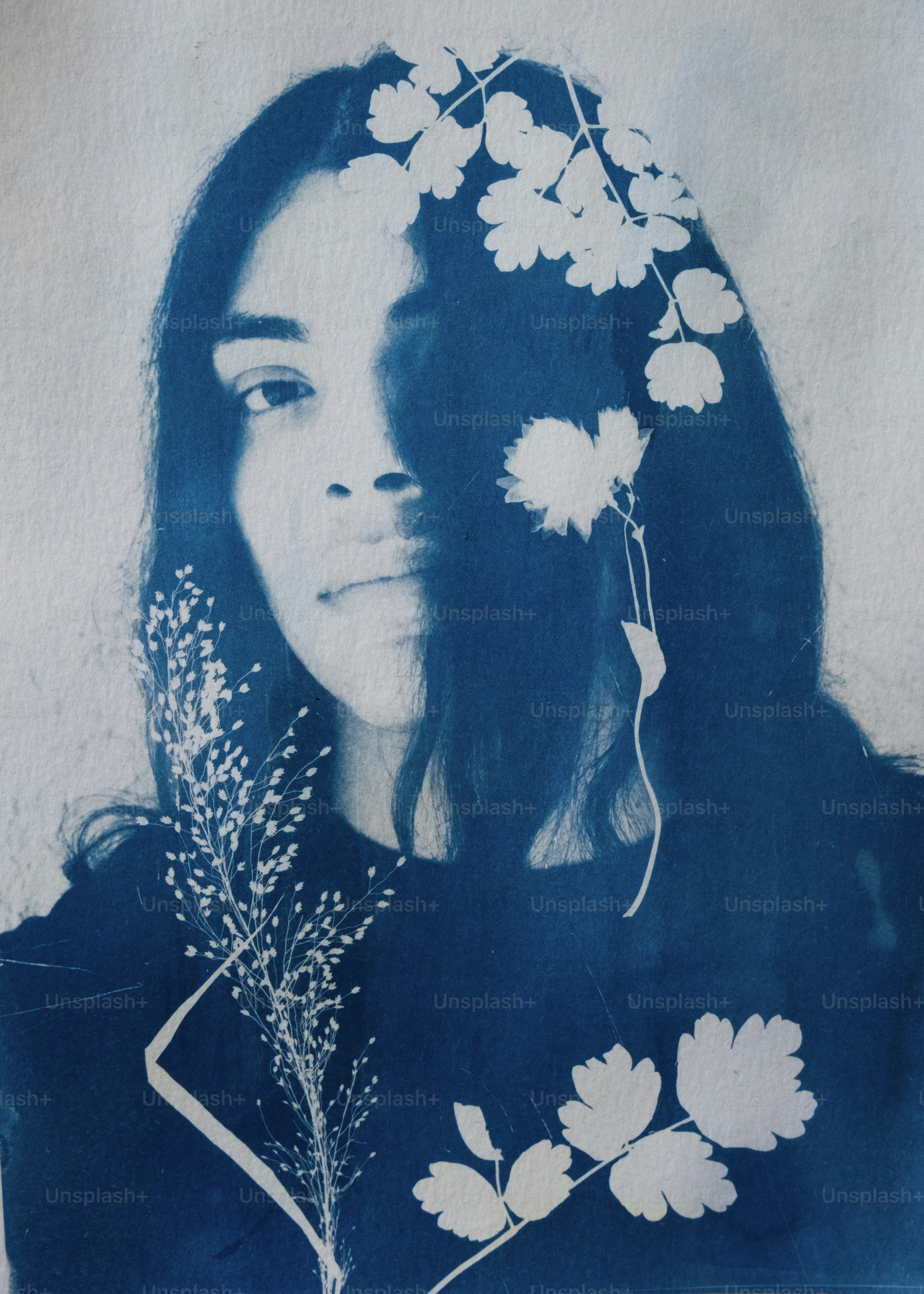 A woman poses amidst leaves and flora. photo – Cyanotype Image on Unsplash