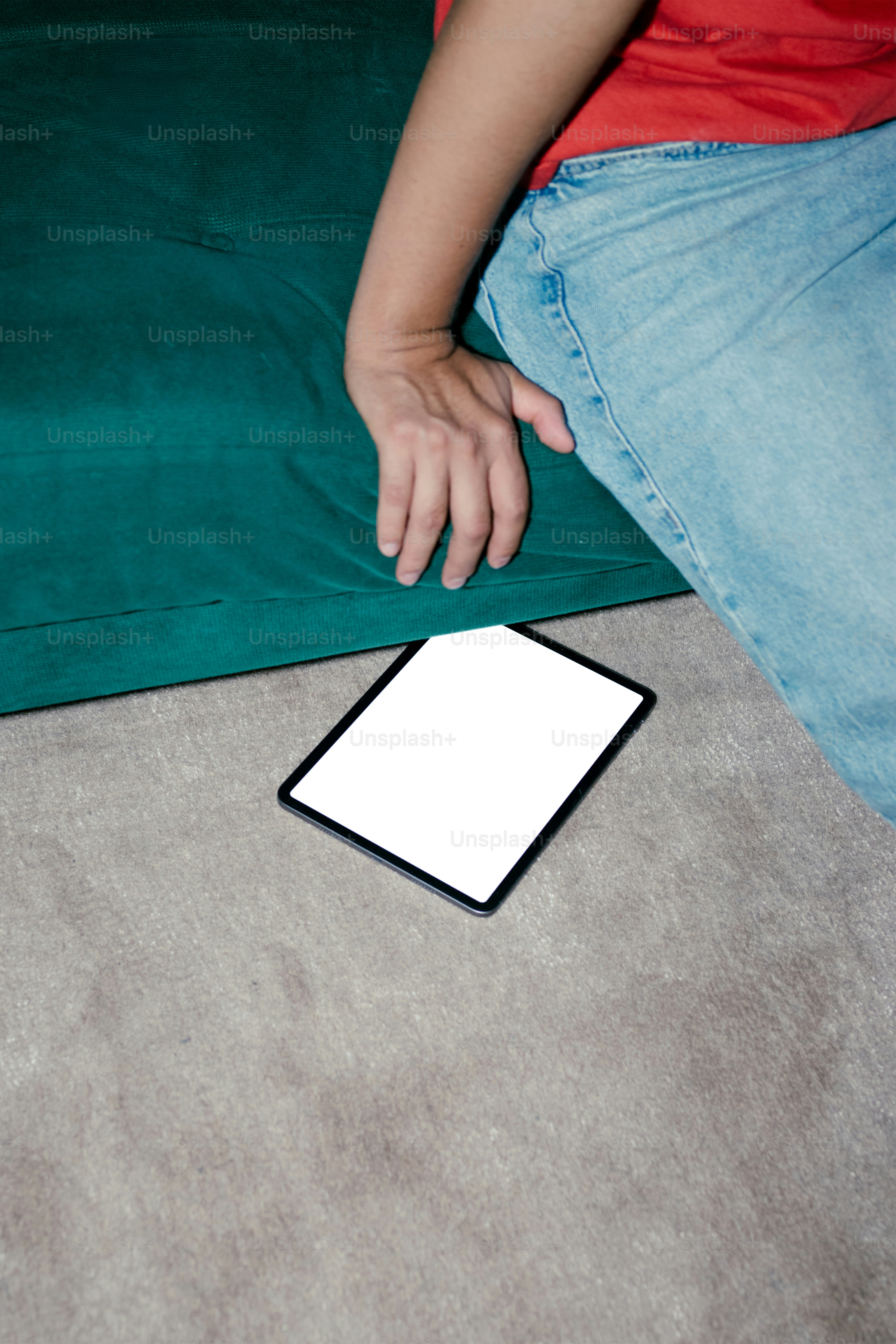 A person rests near a tablet on the floor. photo – Marketing Image on ...