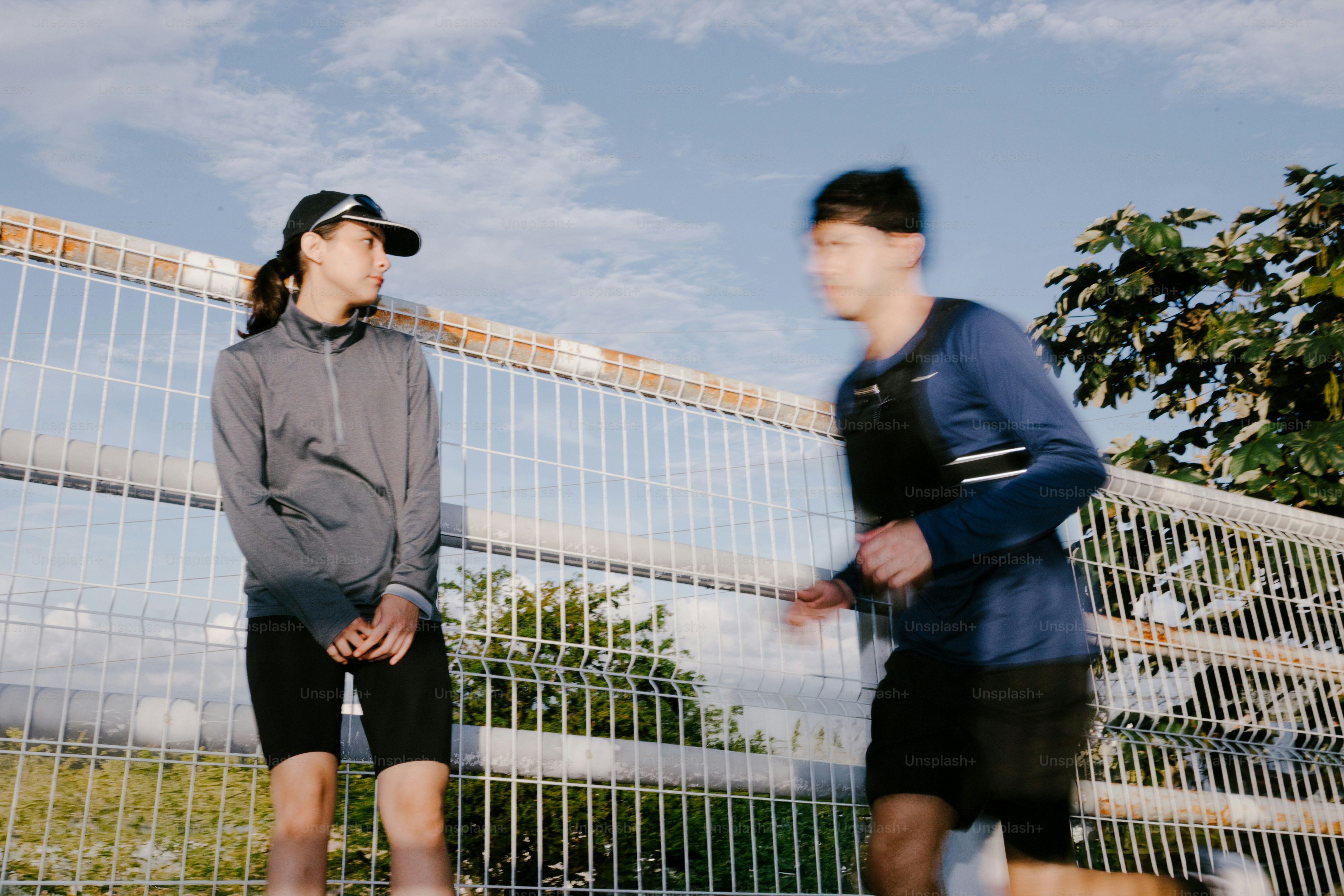 A runner passes a woman leaning on a fence. photo – Sport Image on Unsplash