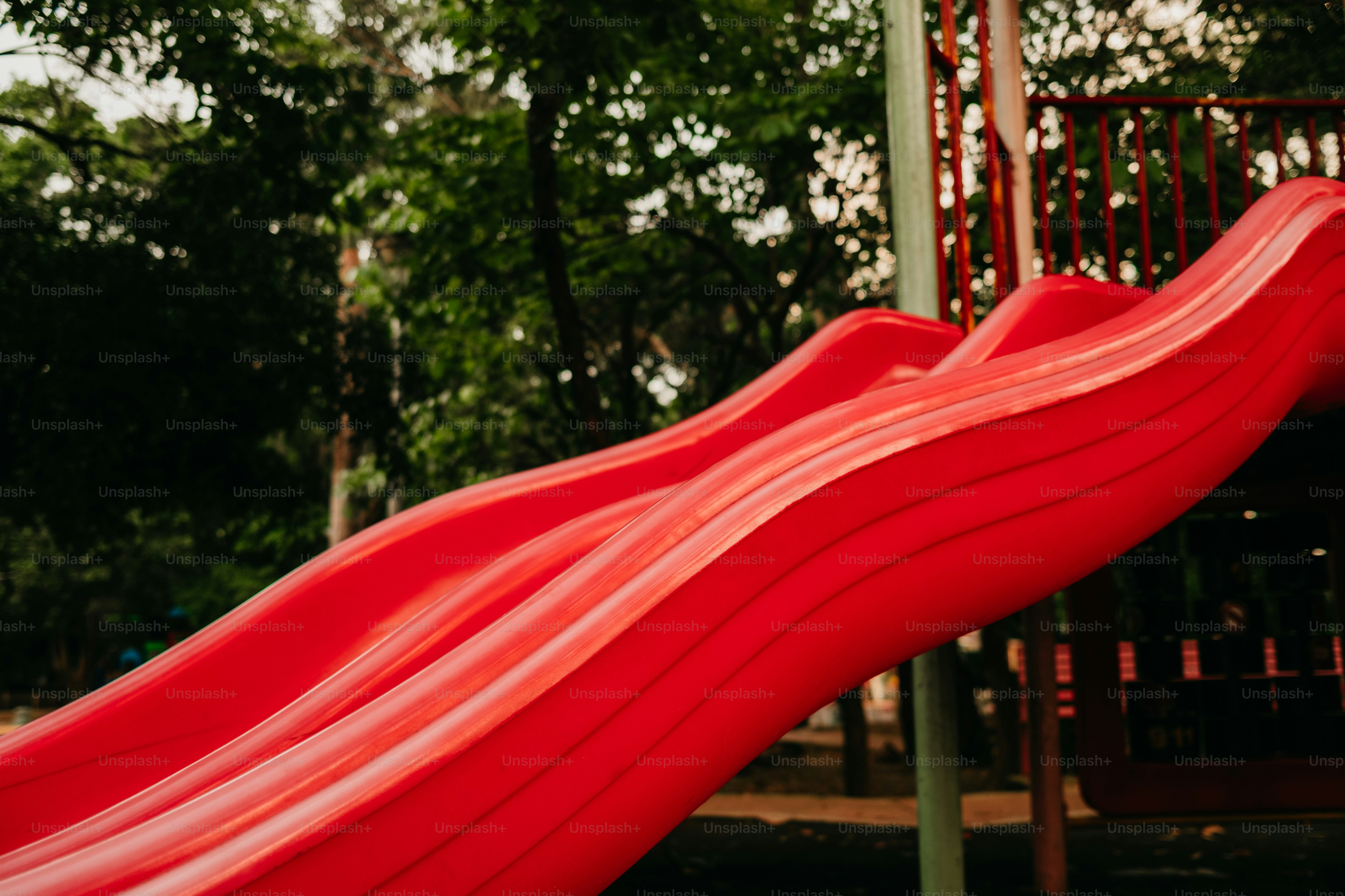 Red slide in the park with a blurry background. photo – Joy Image on ...
