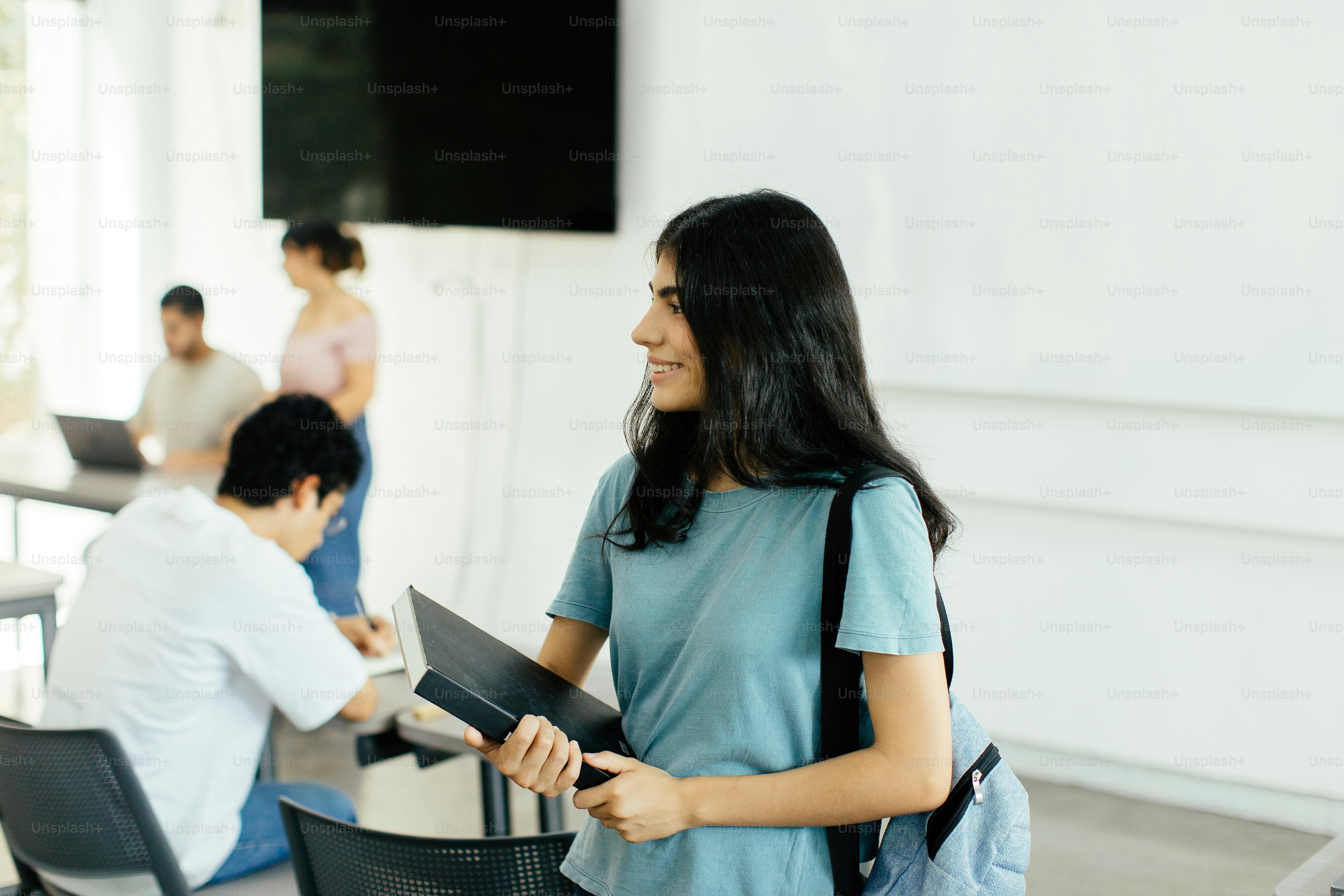 A smiling student walks into a classroom. photo – School Image on Unsplash