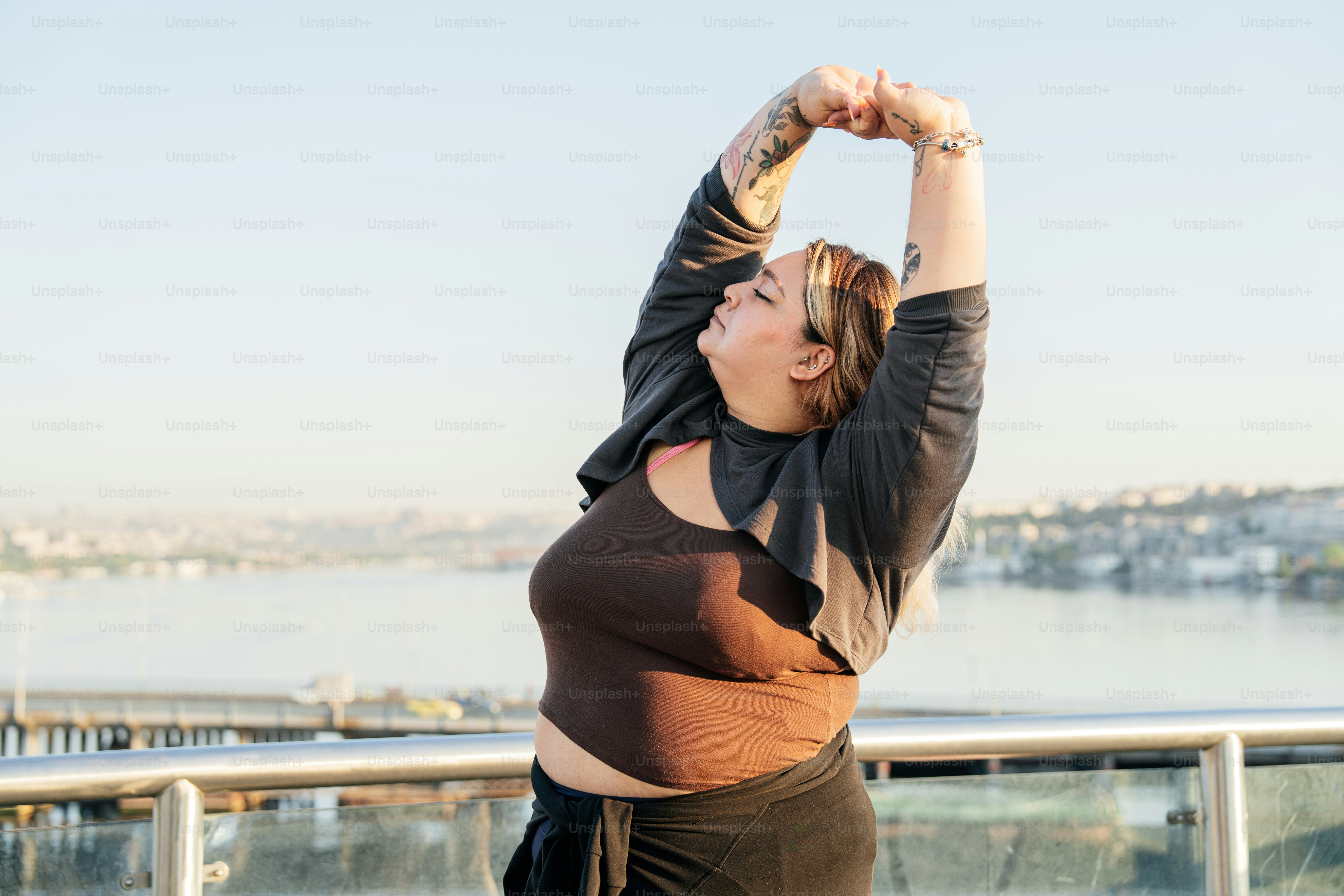 Woman stretches arms overhead on a sunny day. photo – Diversity Image ...