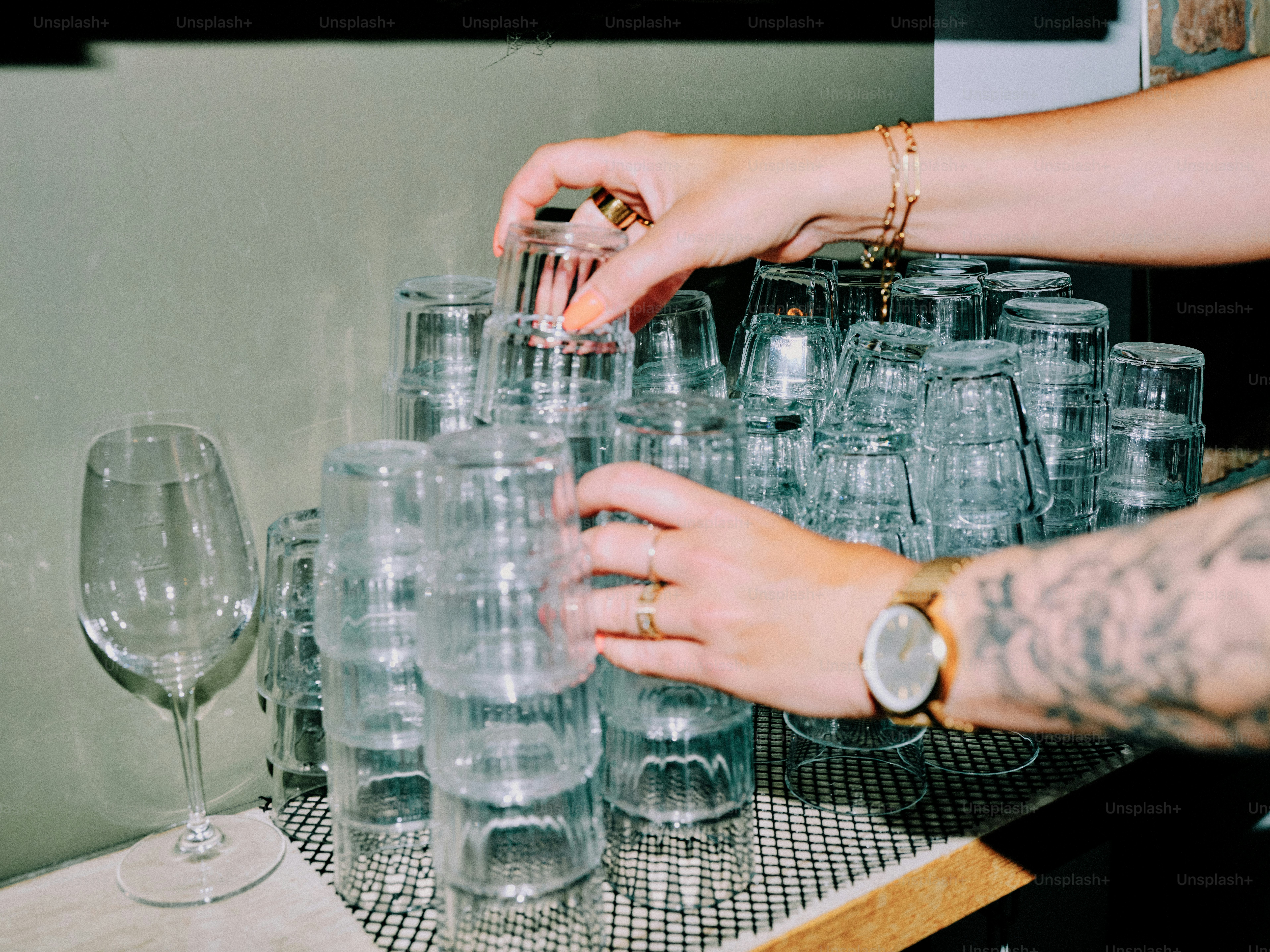 Hands stacking clean glasses at a bar. photo – Wine Image on Unsplash