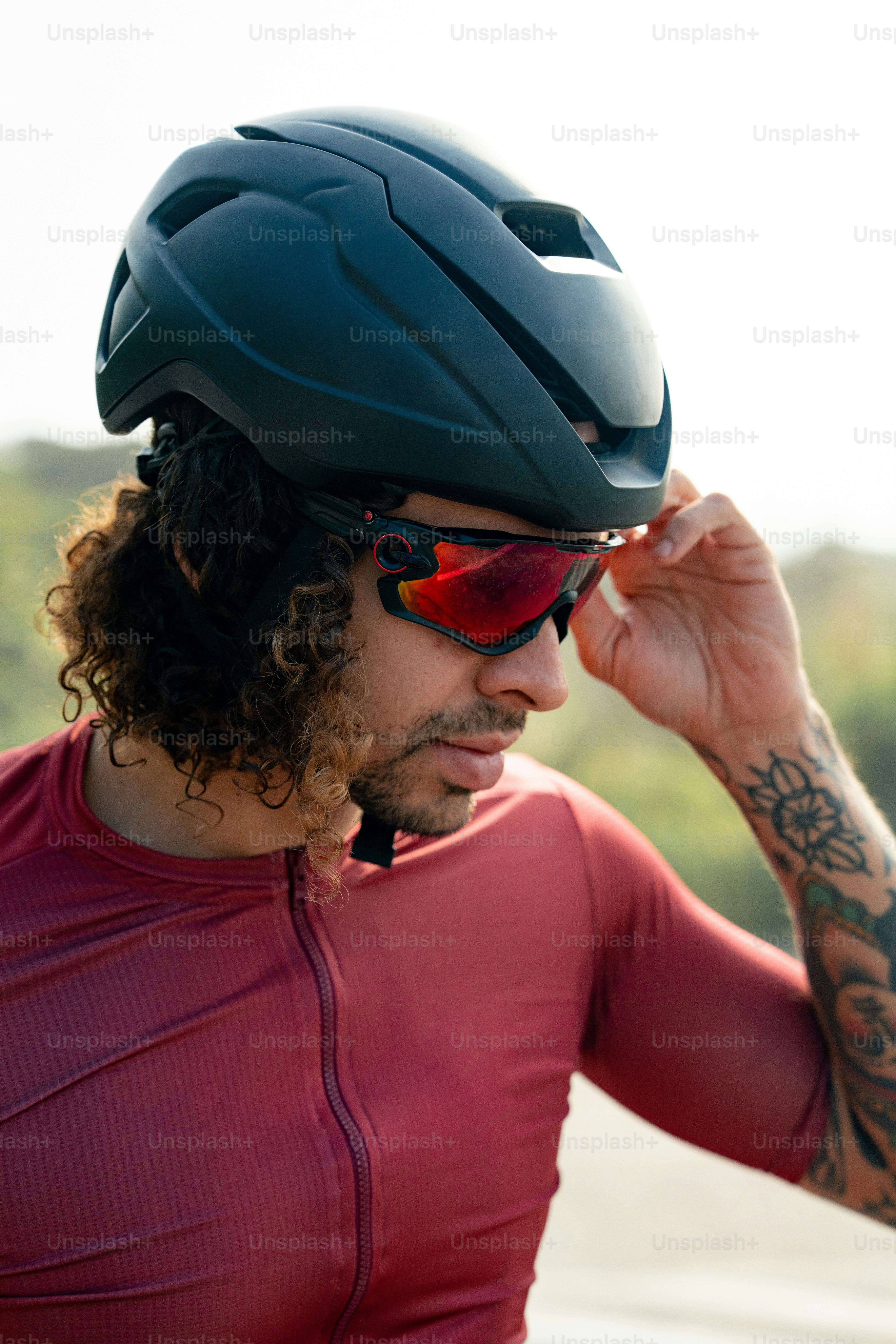 Cyclist adjusting glasses, wearing a helmet and red shirt. photo ...