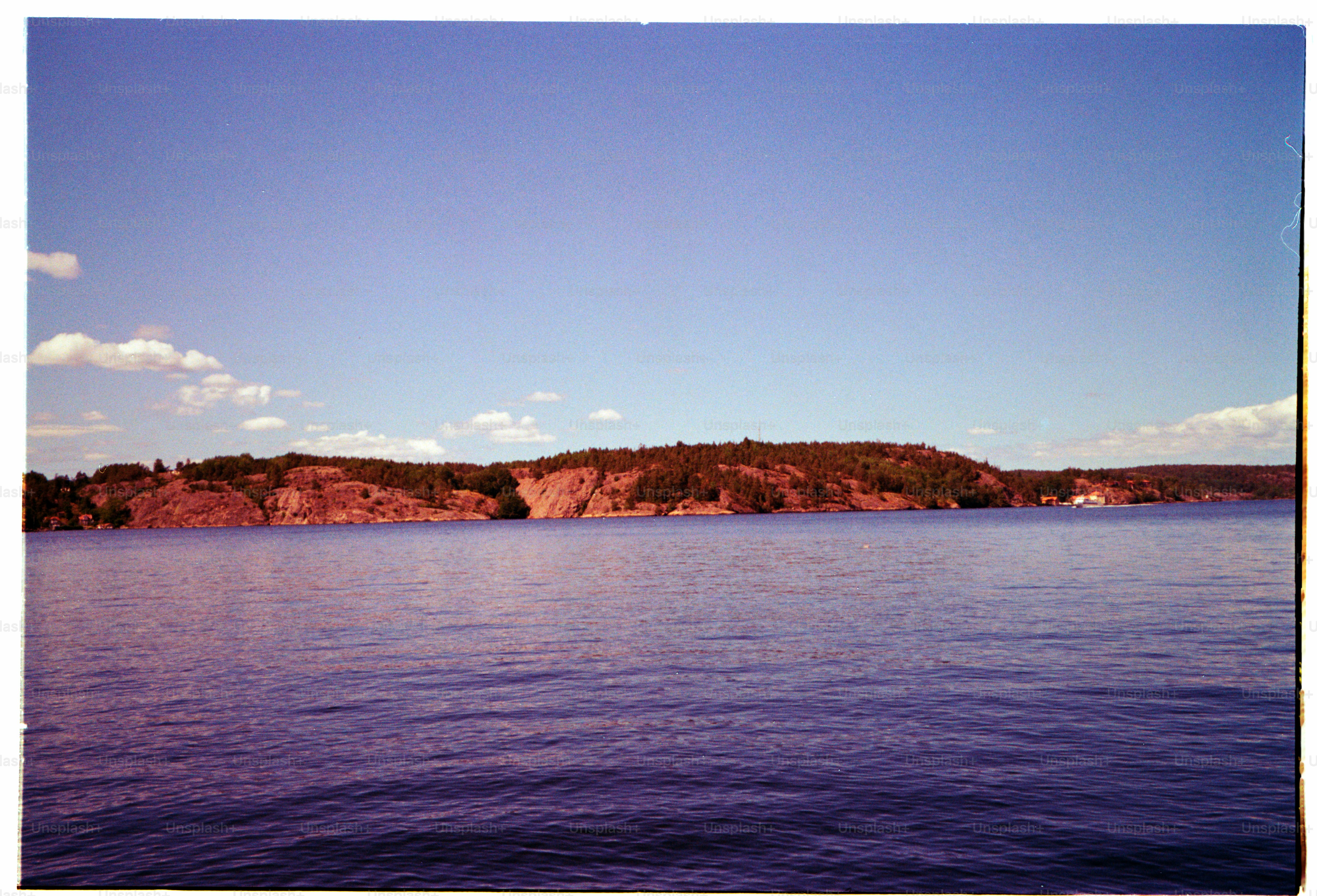 Lake water meets a cliffside under a blue sky. photo – Sweden Image on ...