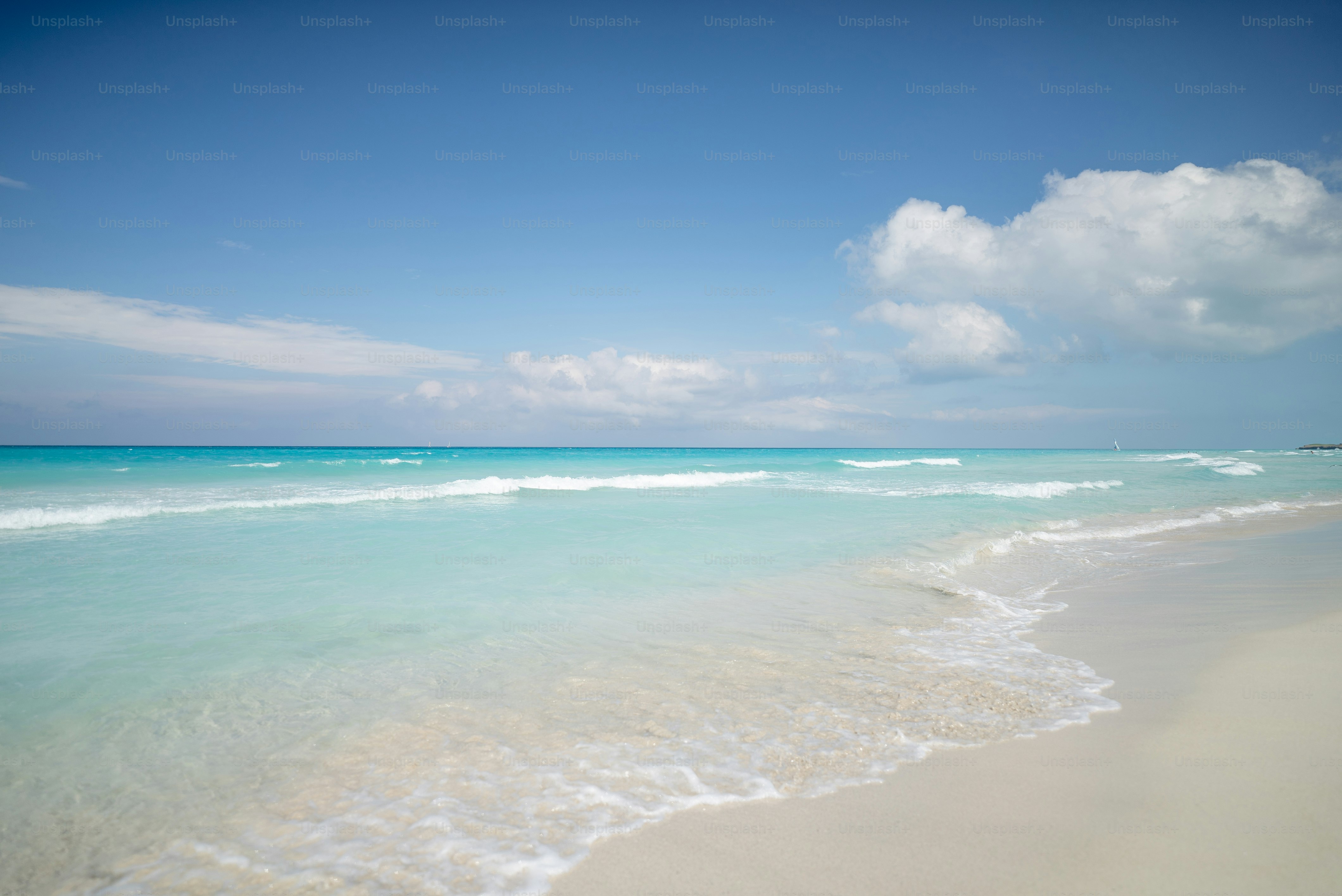 De douces vagues clapotent sur le sable doux sous un ciel bleu clair ...