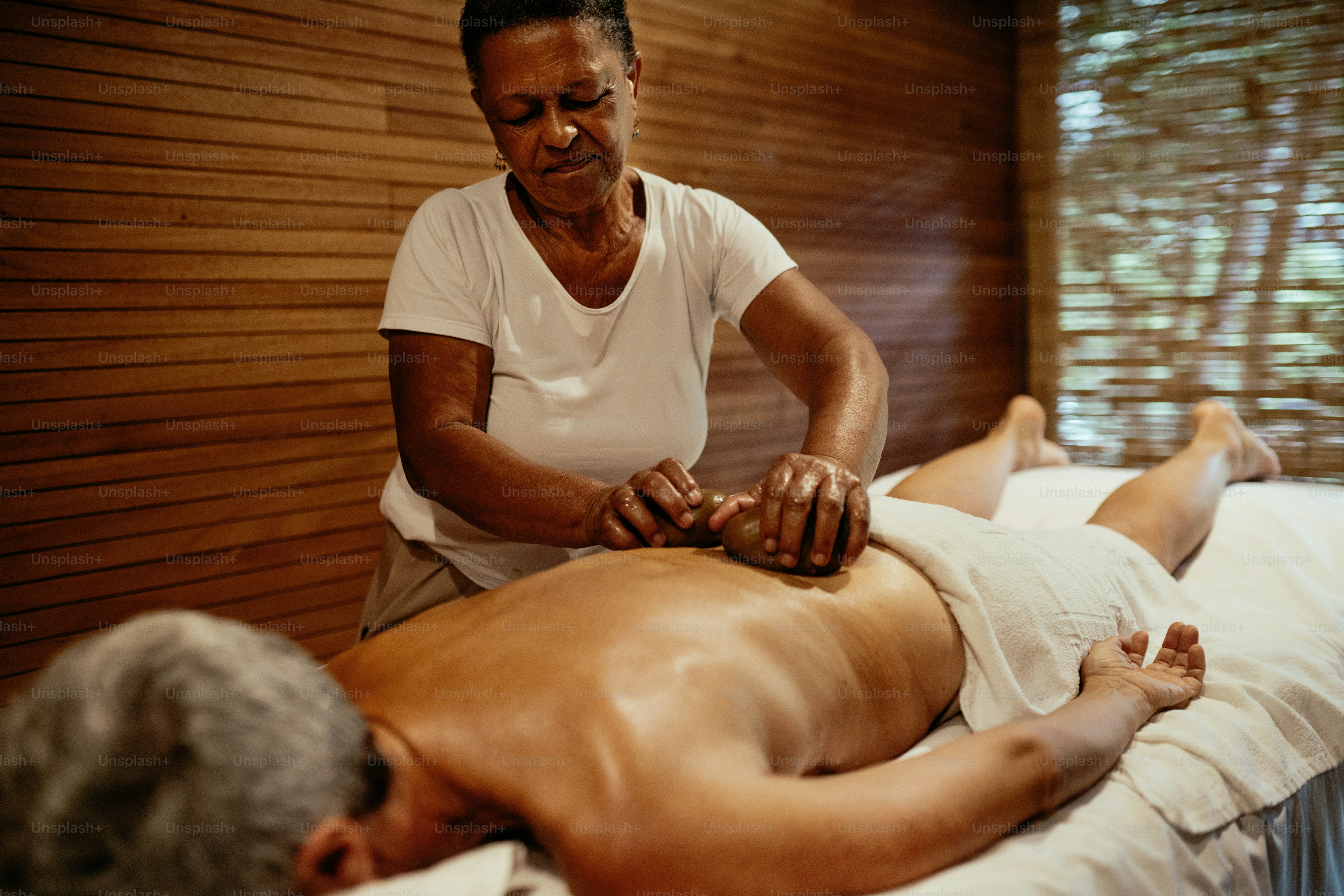 Masseuse giving massage to a mature woman in a luxury spa photo – Adult ...