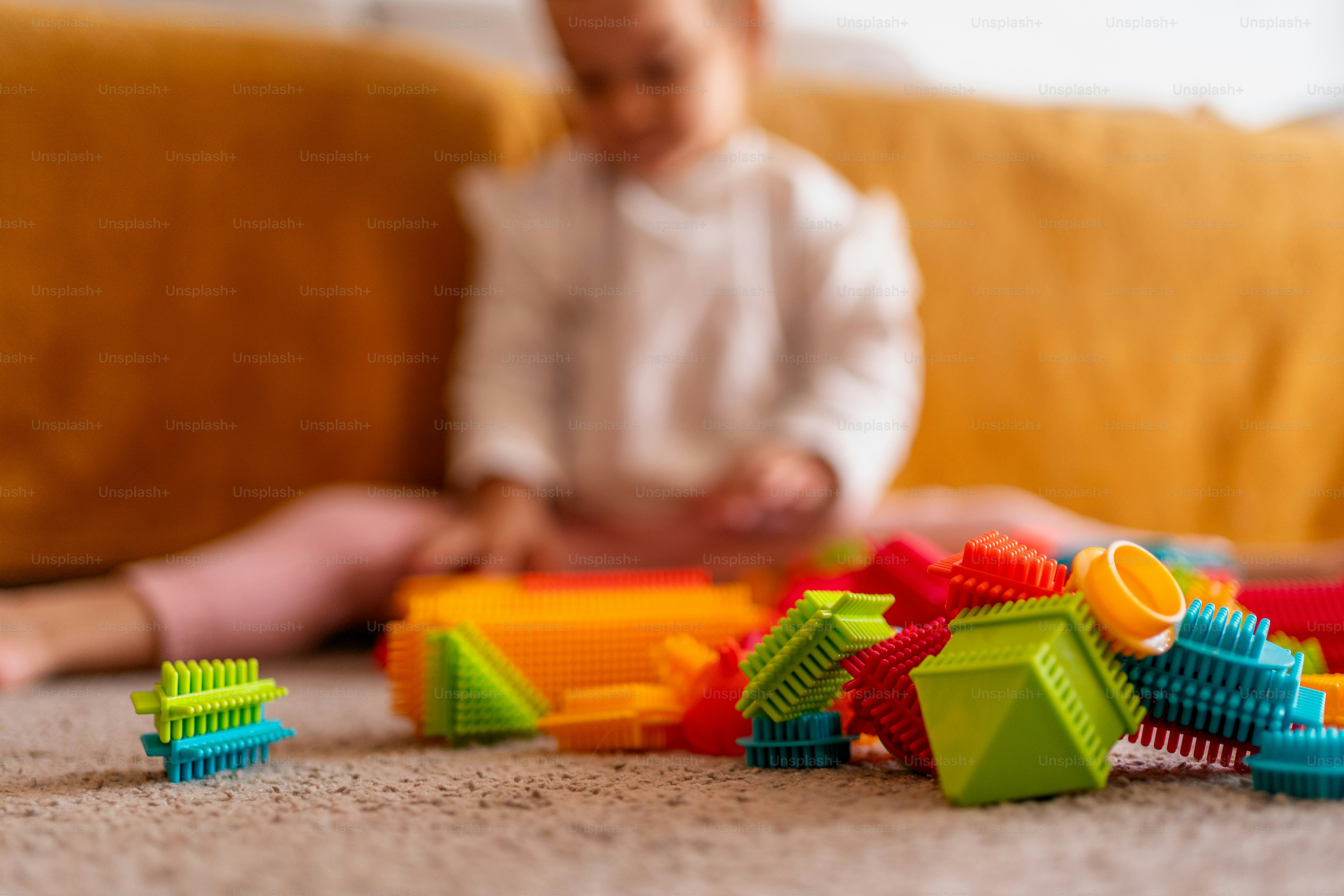 Colorful plastic building blocks laying on carpet with playing child ...