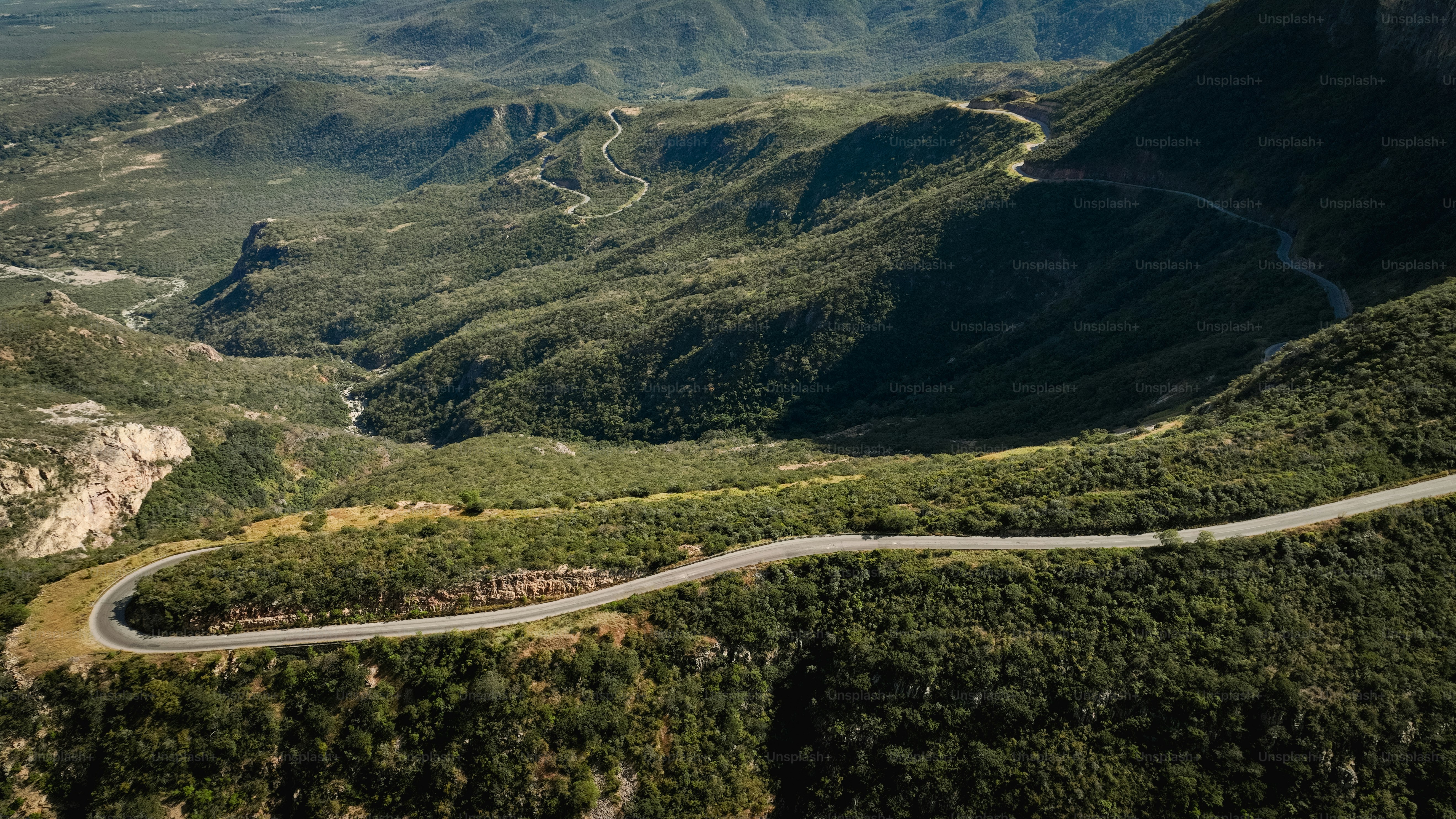 The road snakes through lush green mountains, showcasing the stunning ...