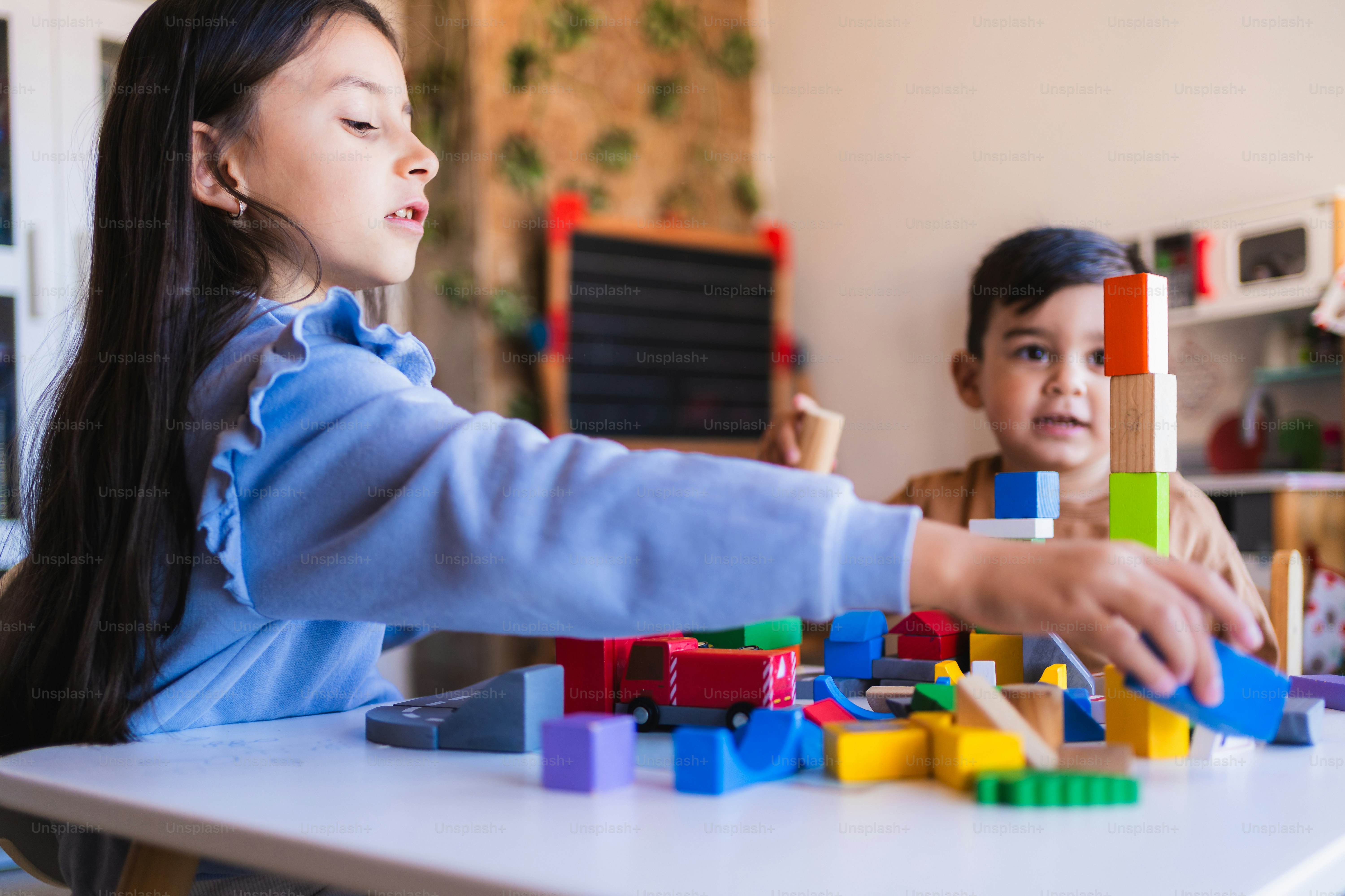 Two young children playing together with colorful building blocks ...