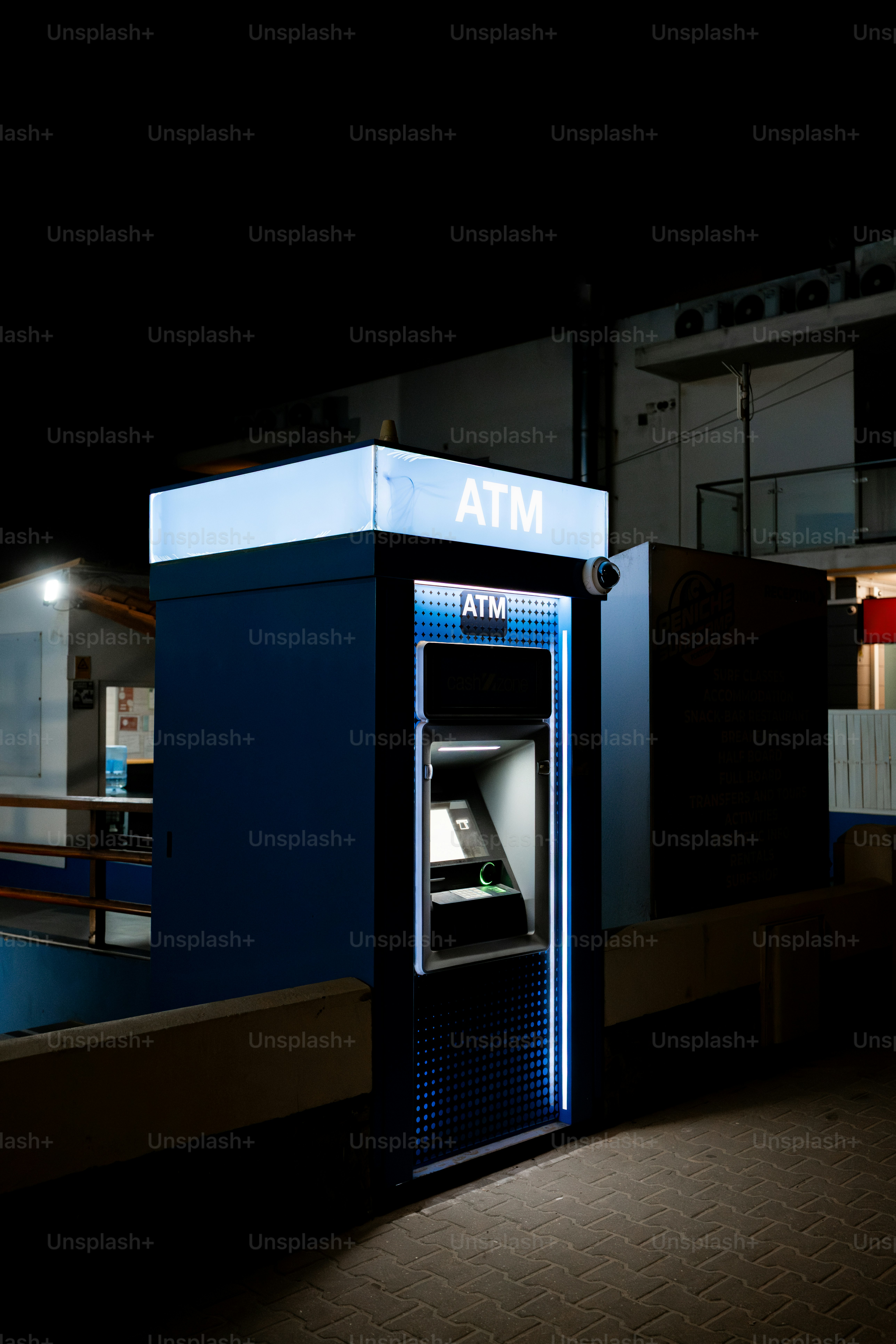 An atm machine illuminated at night on a street. photo – Money Image on ...