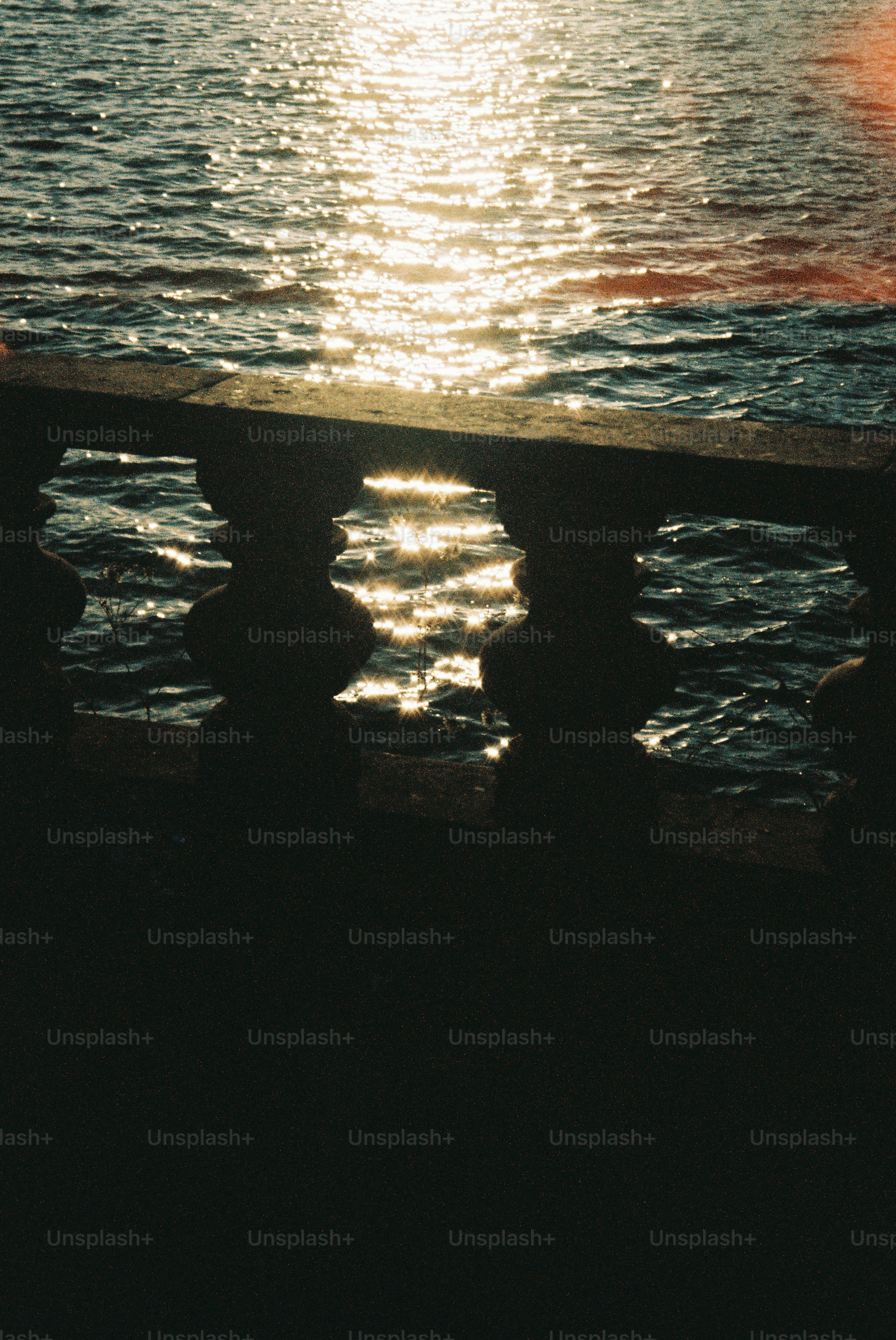Railing with sunlight reflecting on water photo – Sunset Image on Unsplash