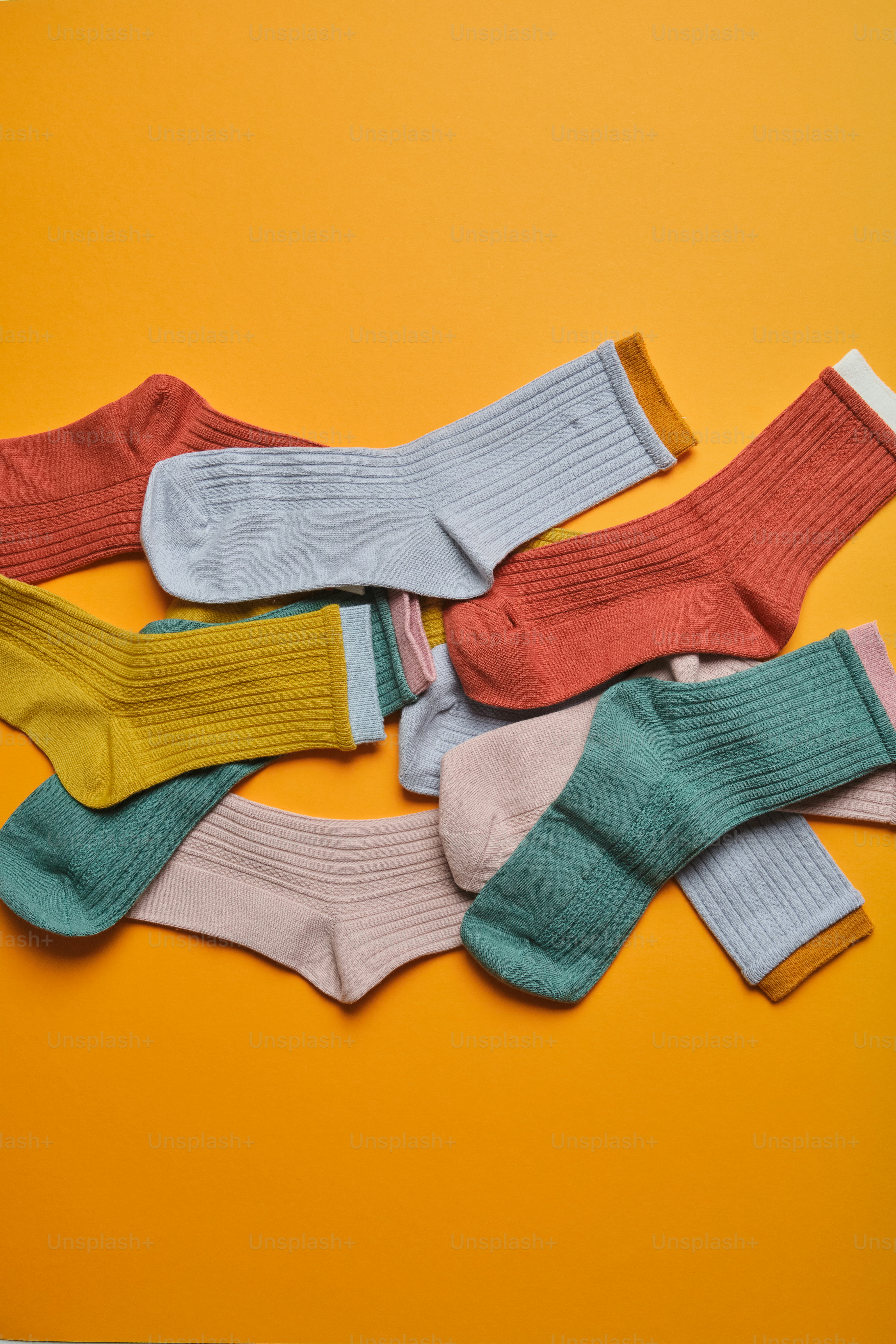 Several pairs of colorful socks scattered on orange photo – Background ...
