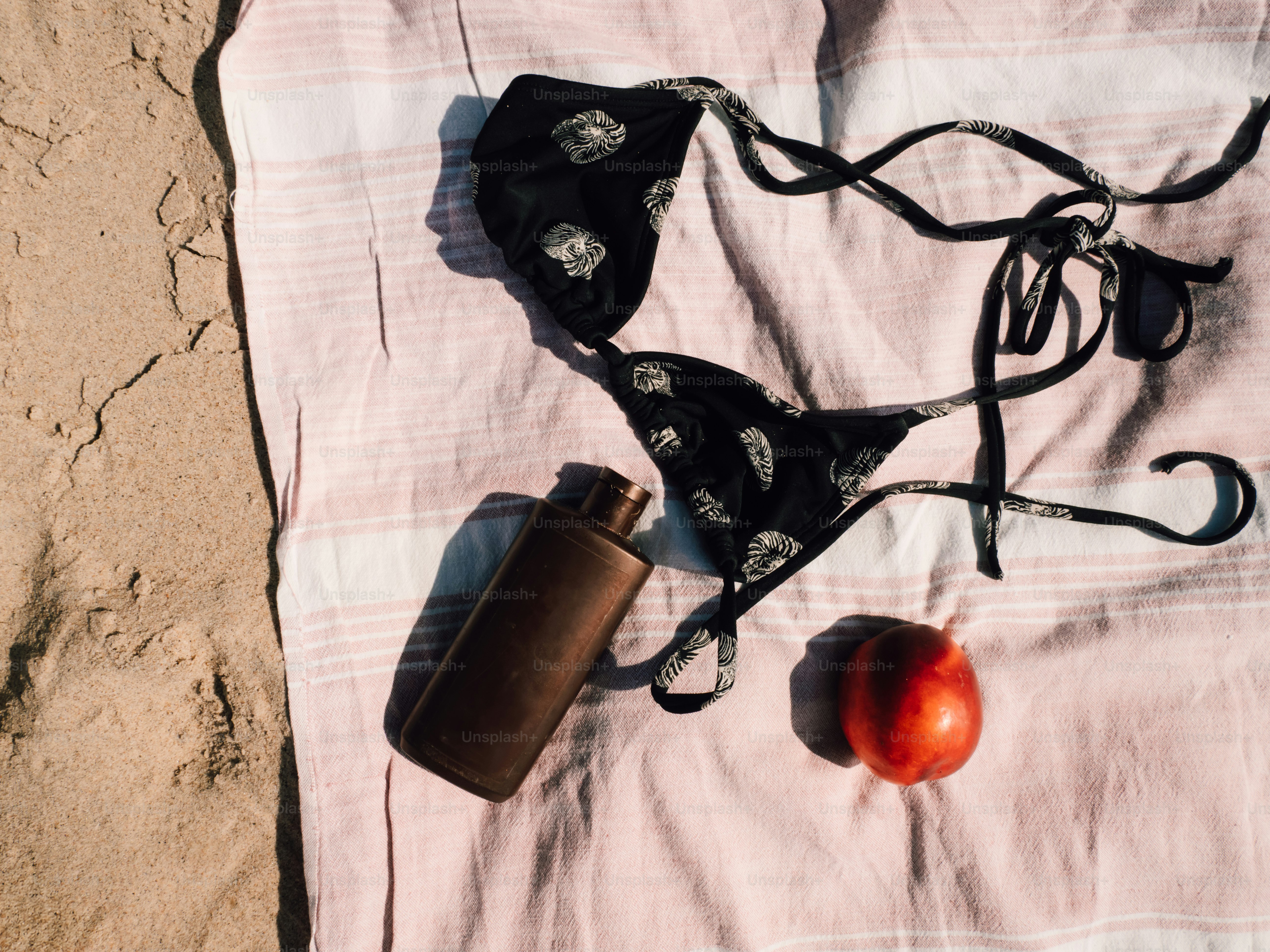 Bikini, sunscreen, and apple on a beach towel. photo – Beach Image on ...