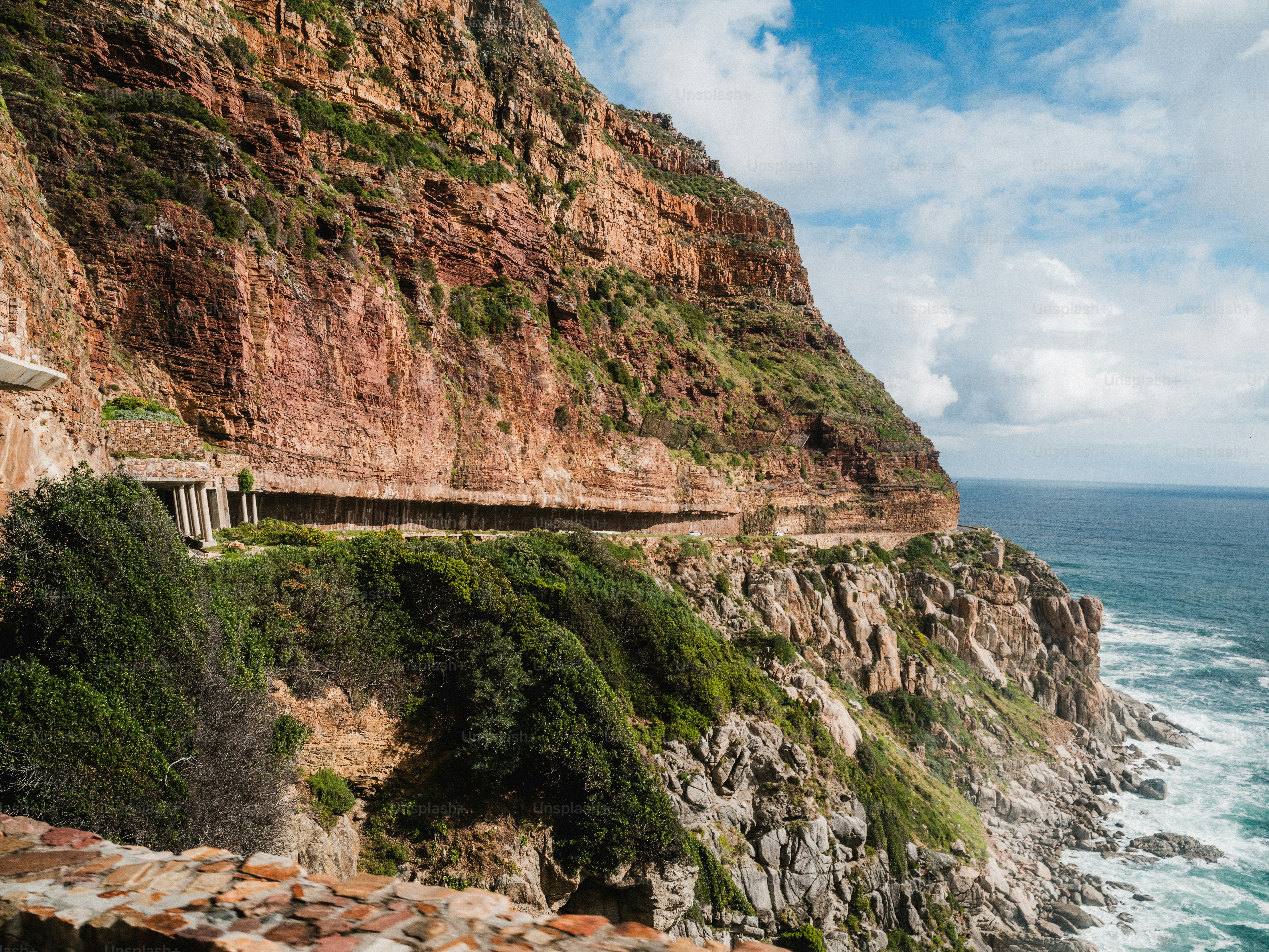 Coastal road carved into a rugged cliffside overlooking the ocean photo ...