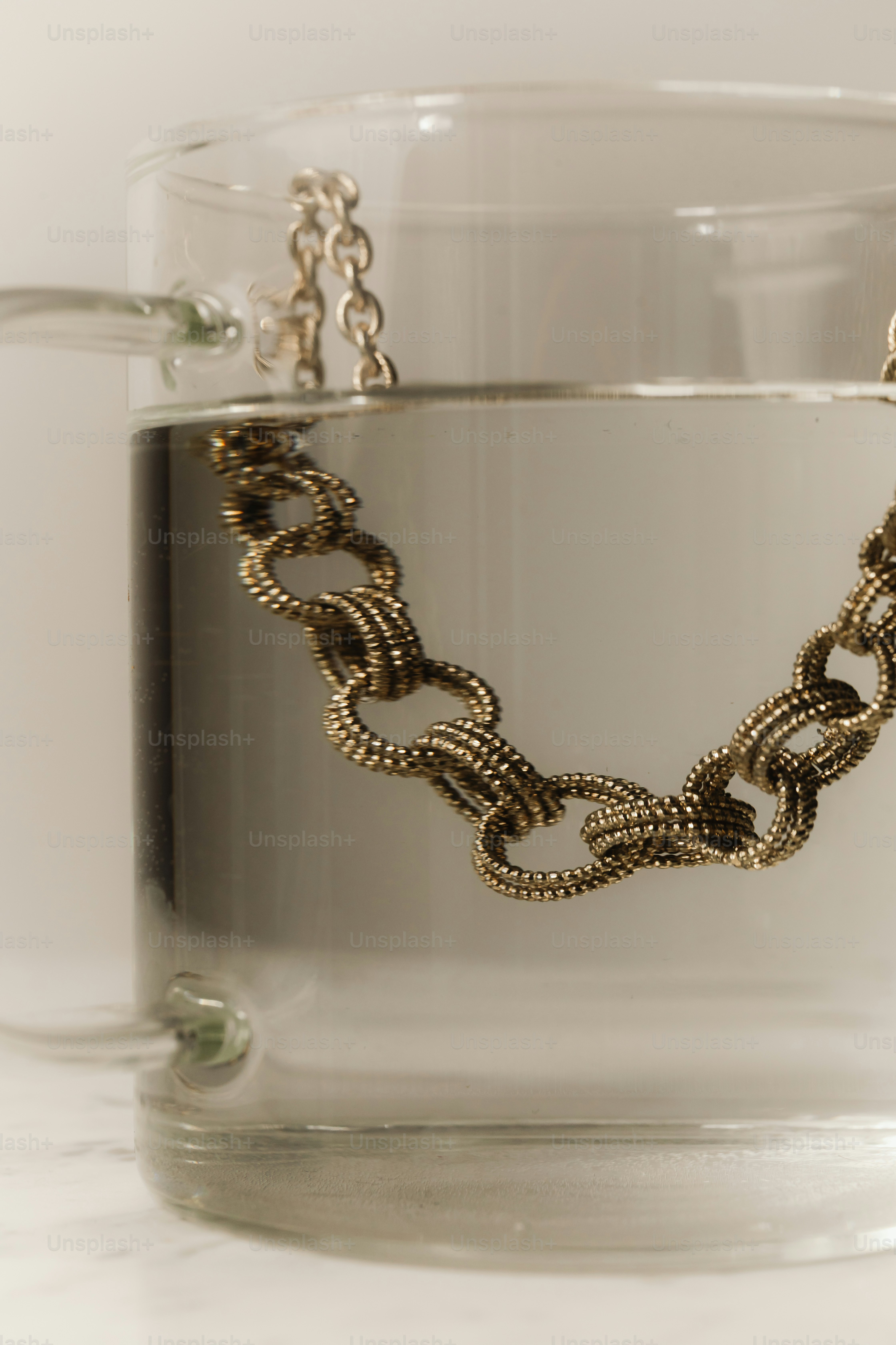 Gold chain draped over a clear glass mug photo – Minimalist Image on ...
