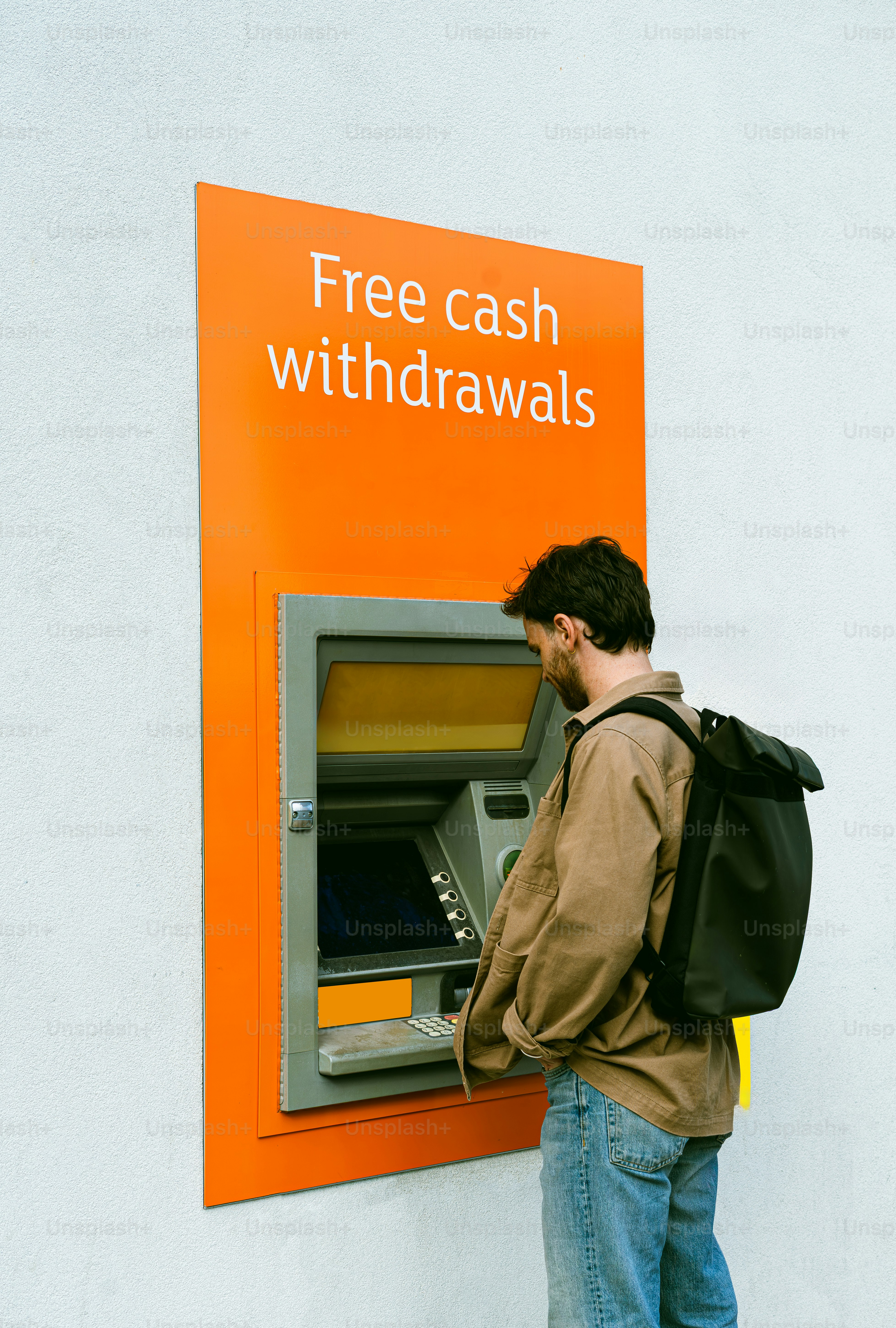 Hand holding orange card near atm with free withdrawals. photo – Money ...