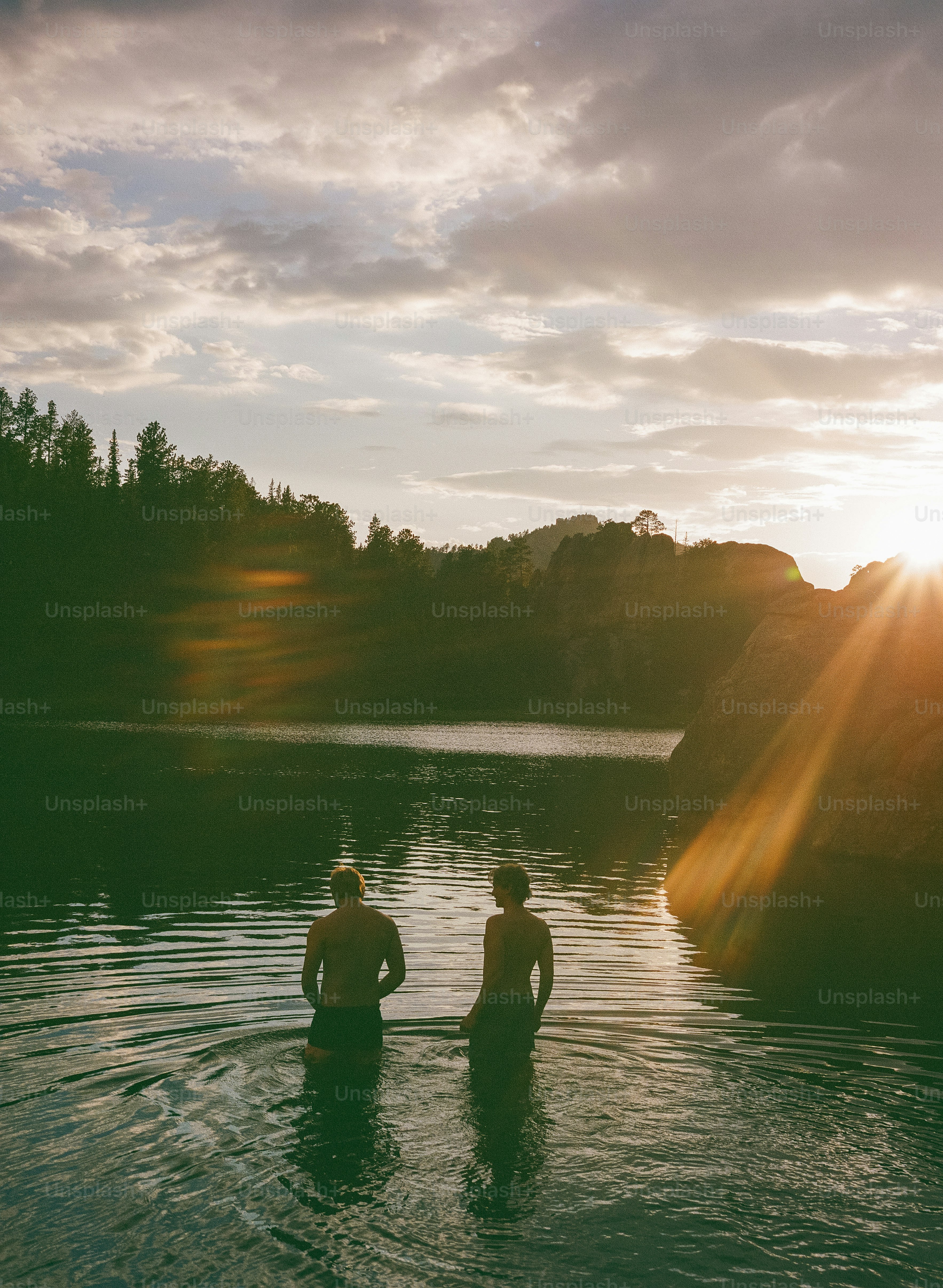 Two people wading into a lake at sunset. photo – Travel Image on Unsplash