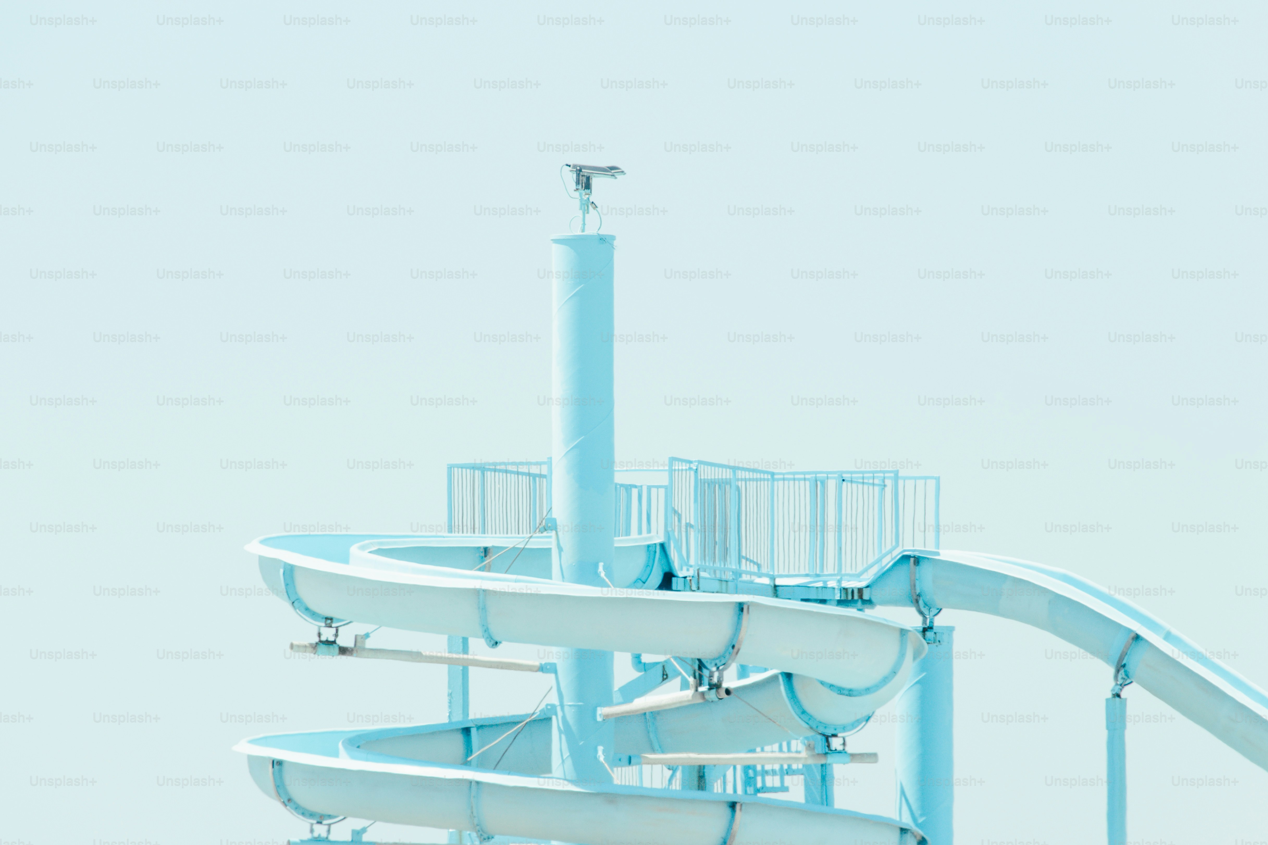 Light blue water slides against a bright sky photo – Architecture Image ...