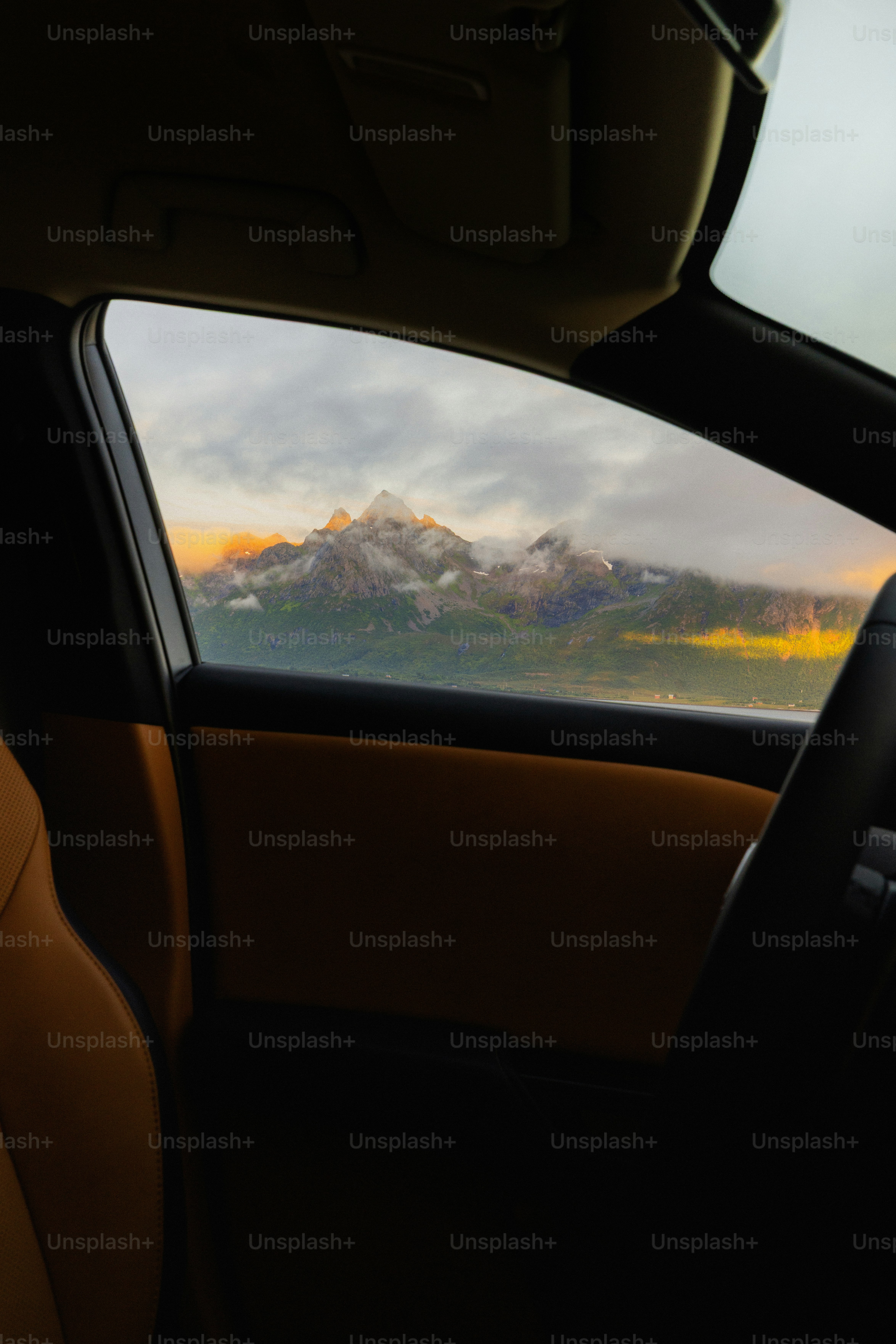 Snow-capped mountains viewed through car window at sunset. photo ...
