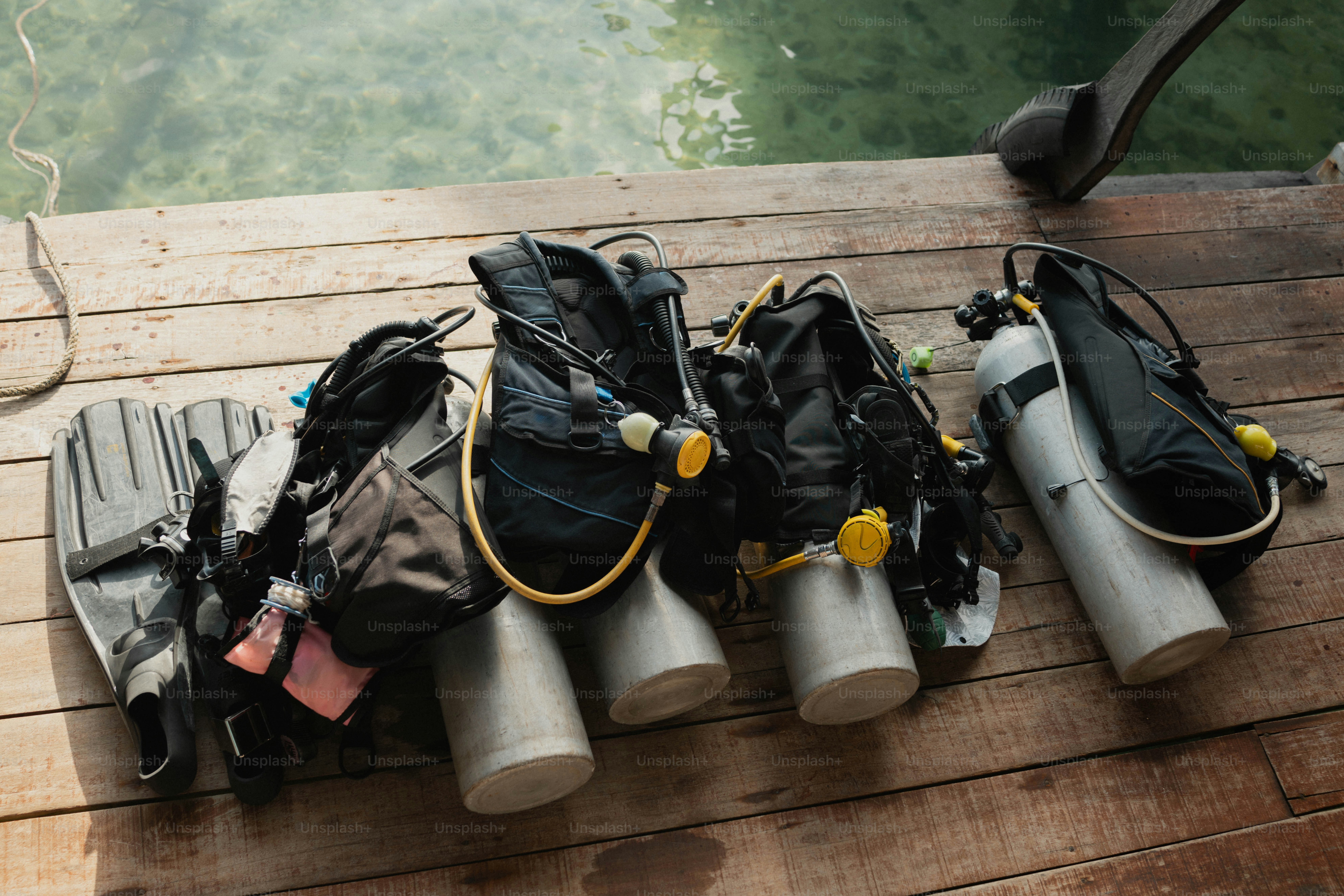Scuba diving gear laid out on wooden planks near water photo – Diving ...