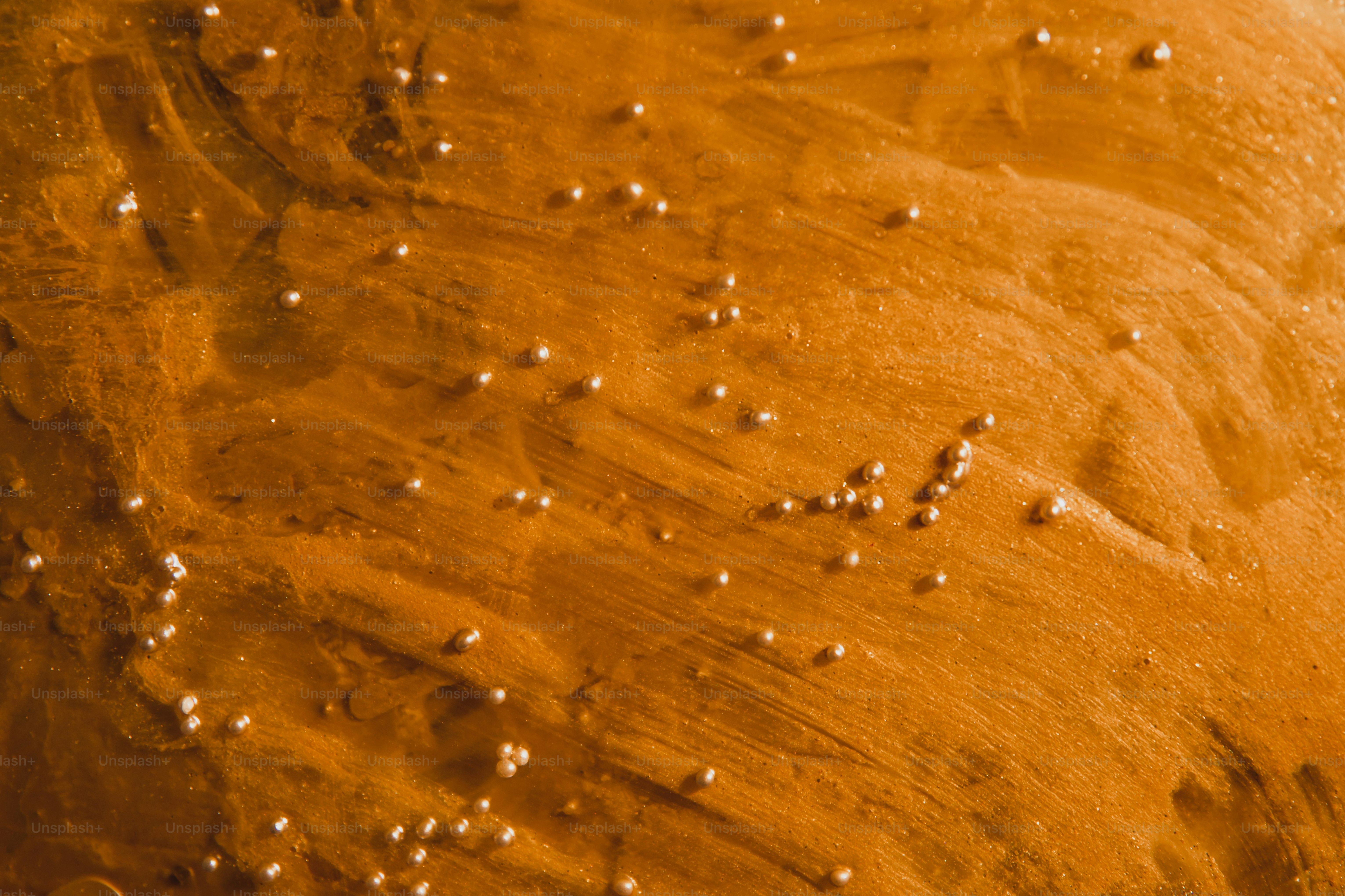 Small white beads scattered on a textured orange surface. photo ...