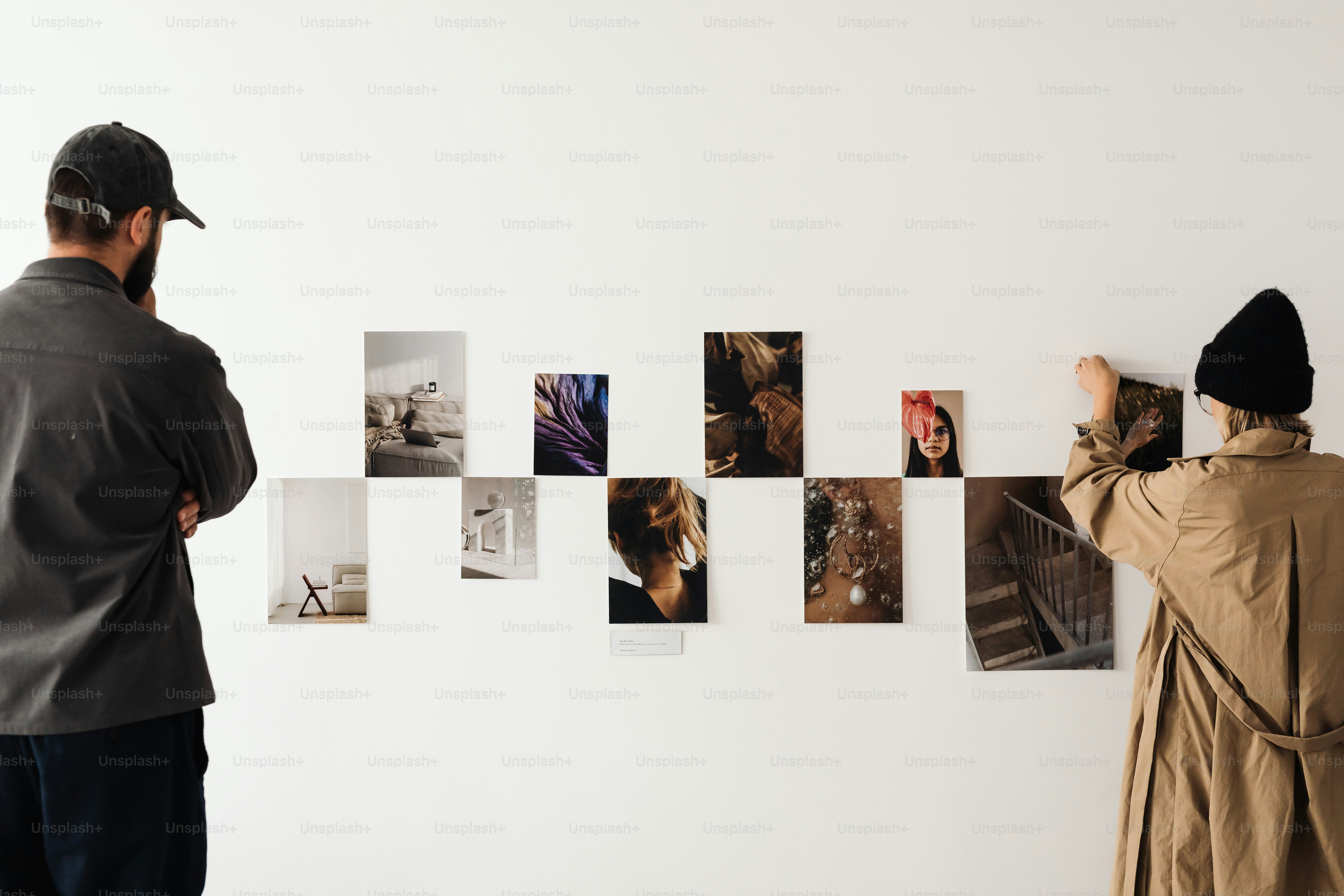 Dos personas arreglando fotos en una pared blanca. foto – Imagen de ...