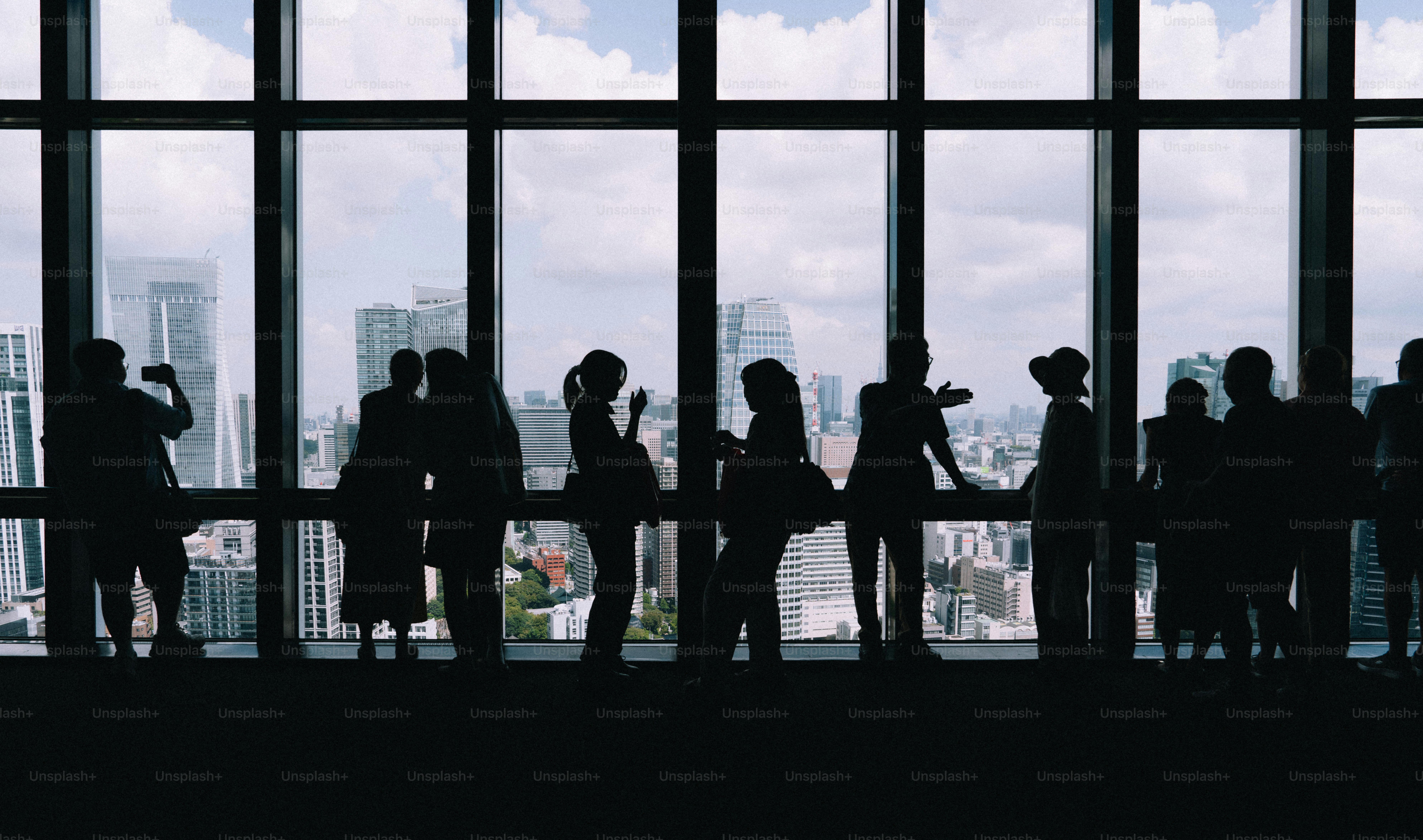 Silhouettes of people looking out large windows at city photo – Japan ...